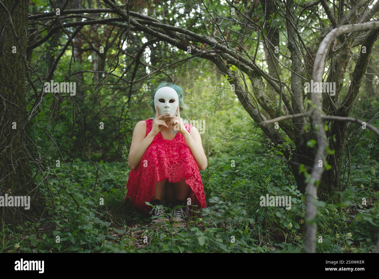 woman hiding her identity behind a white mask in the middle of a ...