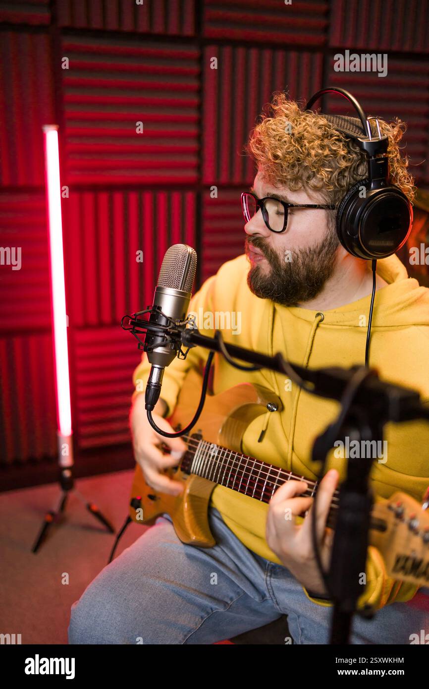 Man vocal artist singing in a recording studio with guitar. Male singer ...