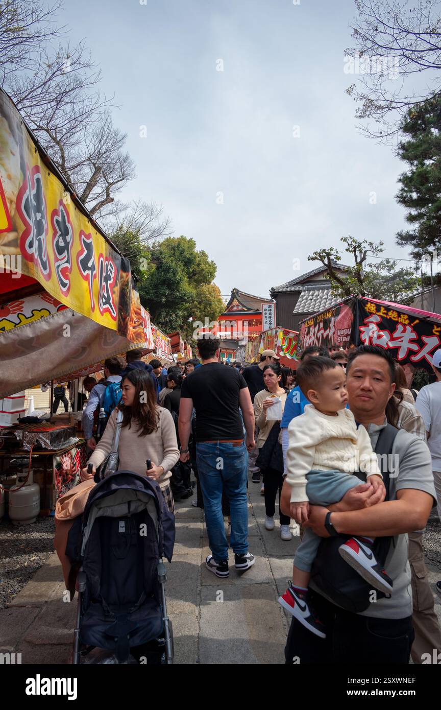 Tourists enjoy Japanese local delicacies in stalls outside the Fushimi ...
