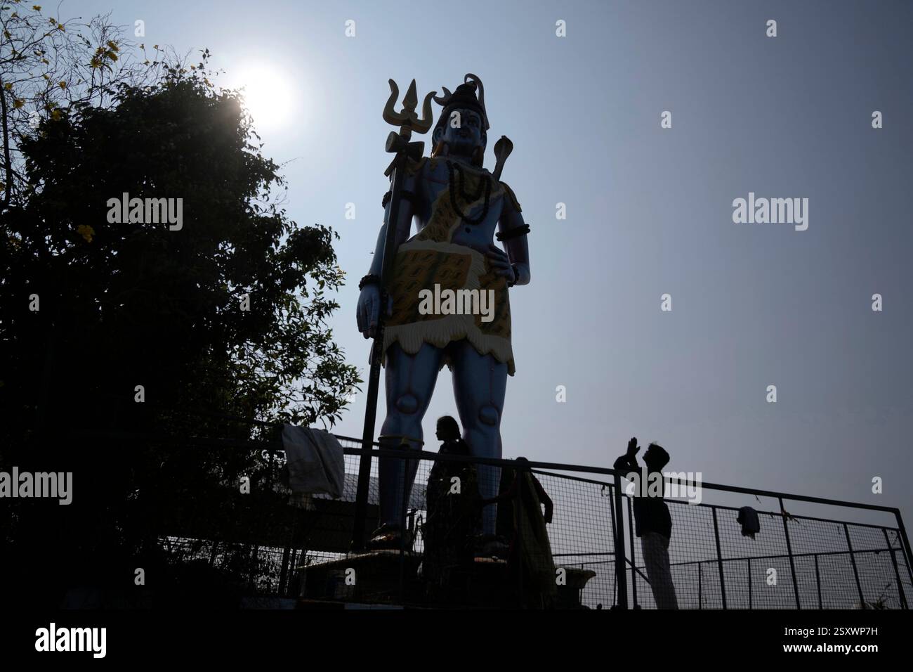 A Hindu devotee prays at a giant statue of Lord Shiva during Shivaratri ...
