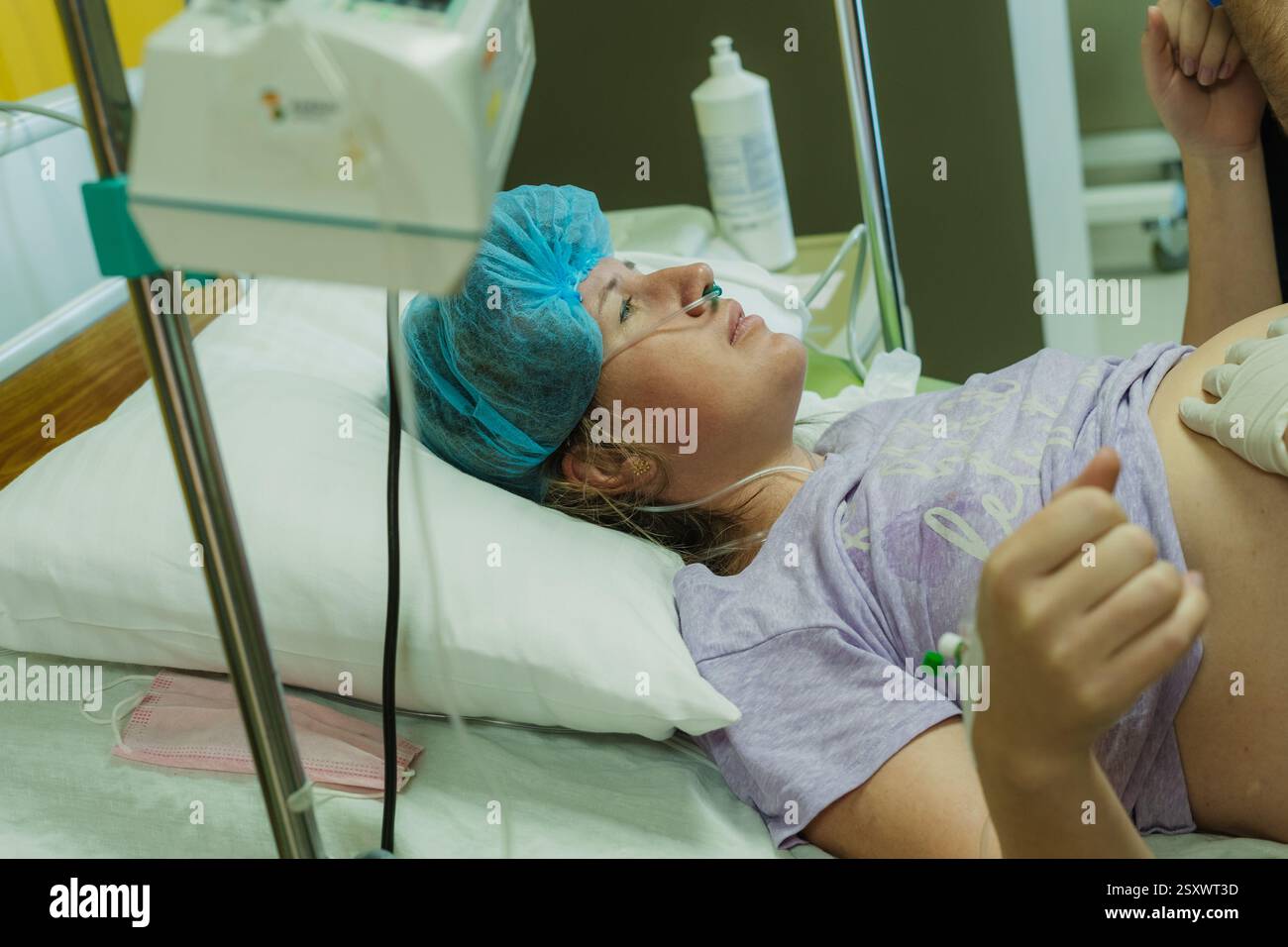A touching moment of childbirth in a hospital. Doctors and staff assist the mother while the ...