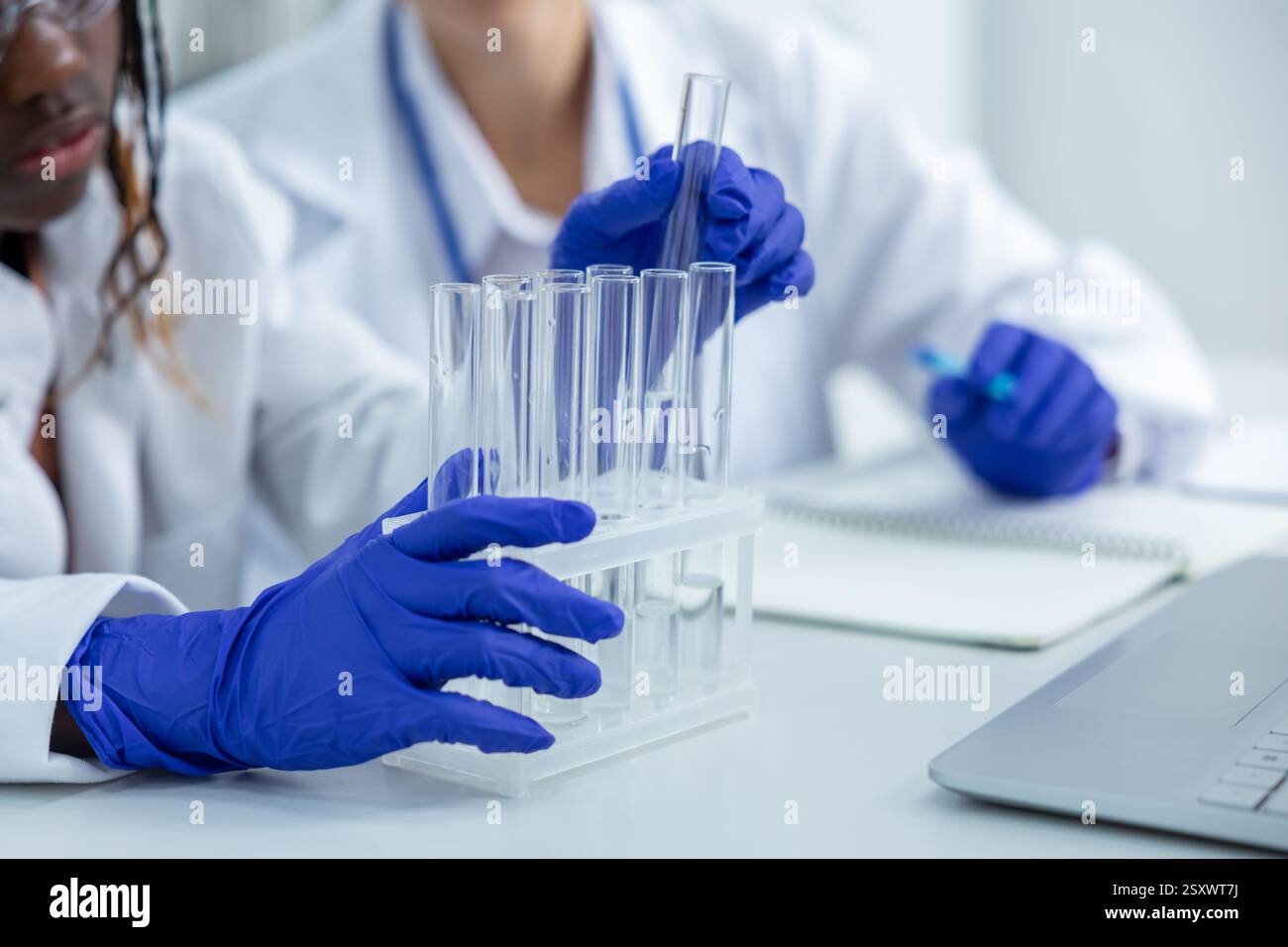 Unrecognizable medical women in lab holding pipettes conducting test on ...