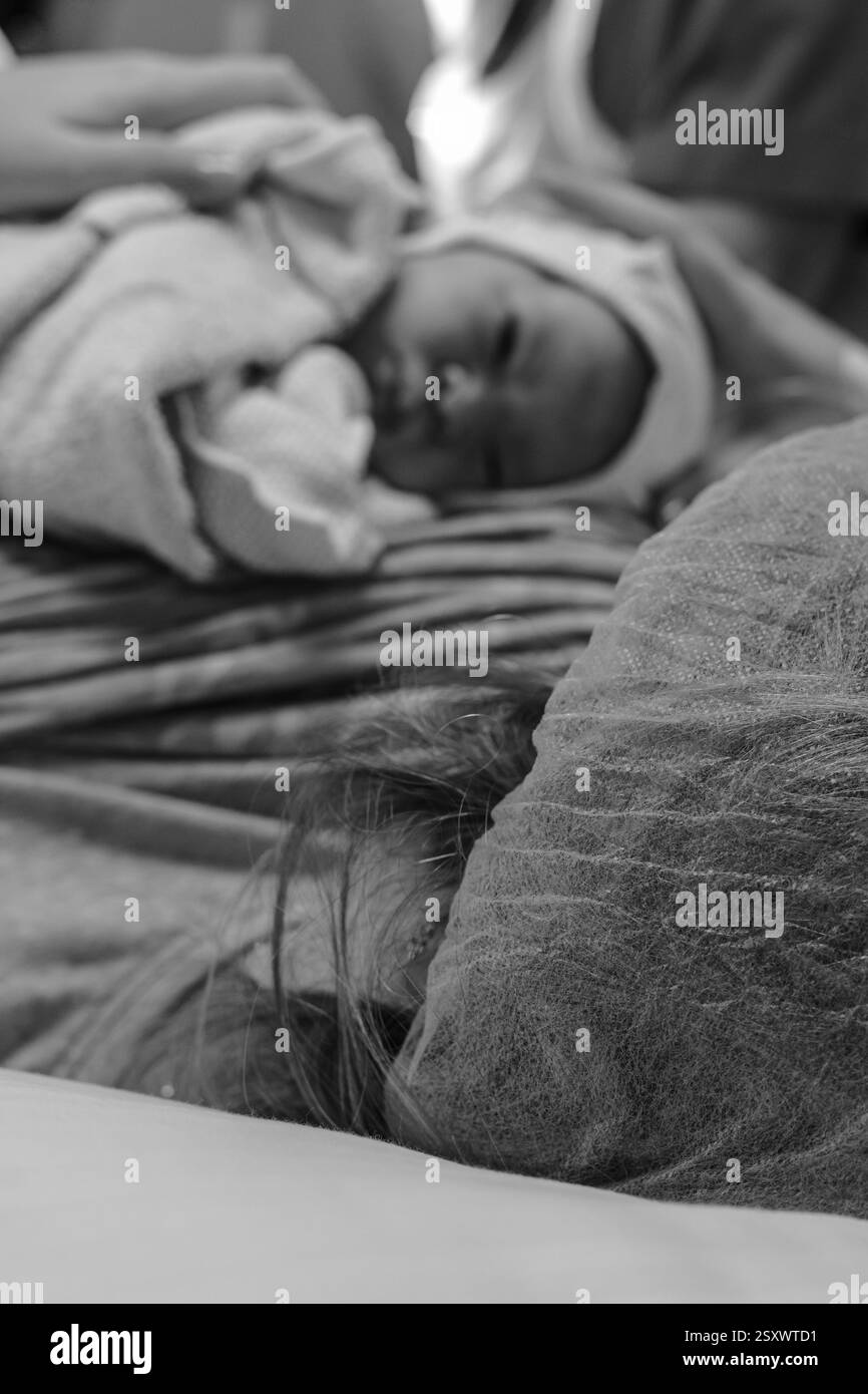 A touching moment of childbirth in a hospital. Doctors and staff assist the mother while the ...