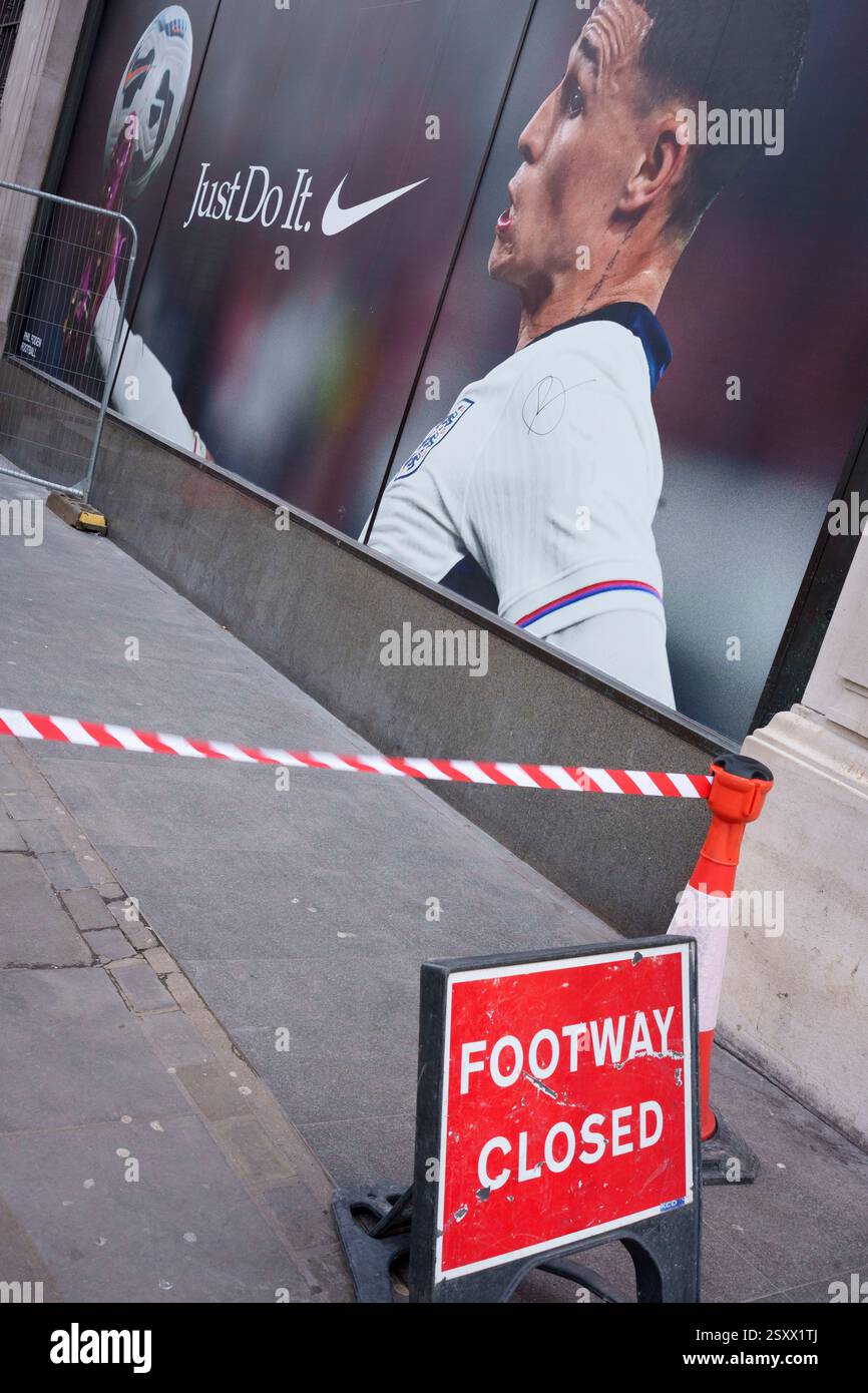 A closed footway is taped off for construction and a 'Just Do It' ad ...