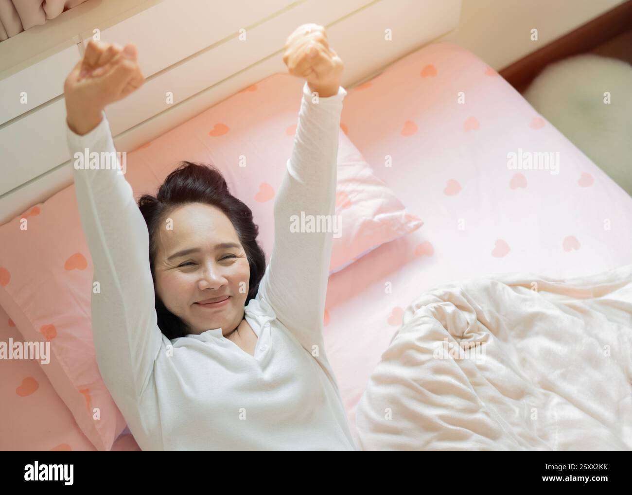 Smiling Asian lady awake after healthy sleep and laying in cozy ...