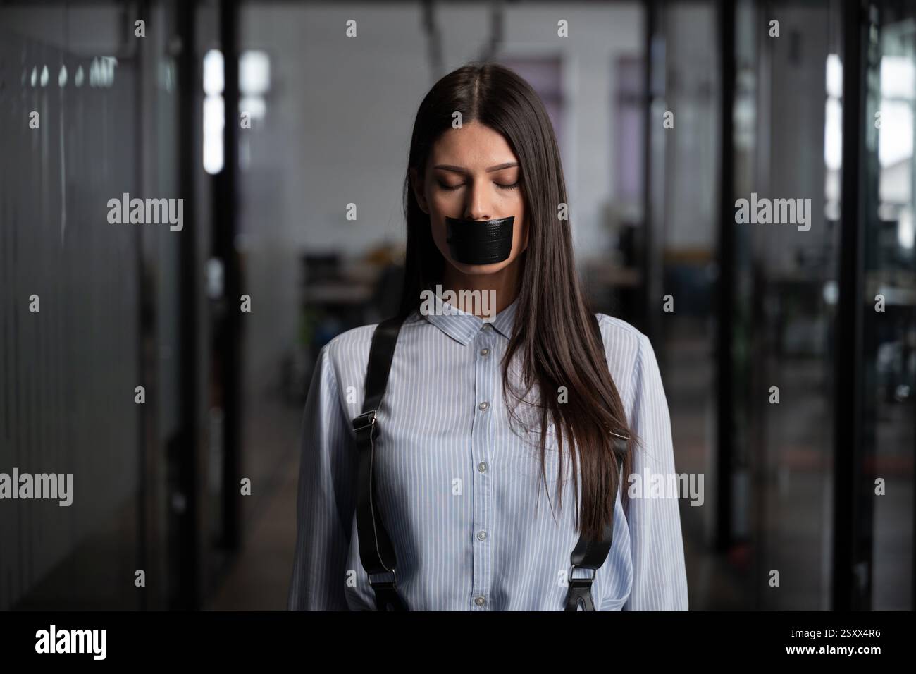 Young woman with long hair and closed eyes standing in an office ...