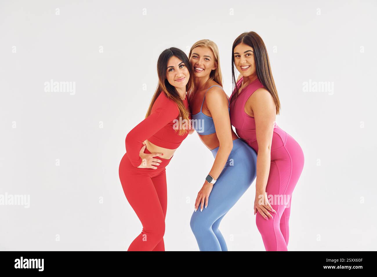 Standing and smiling. Beautiful women in sportive clothes is indoors in ...