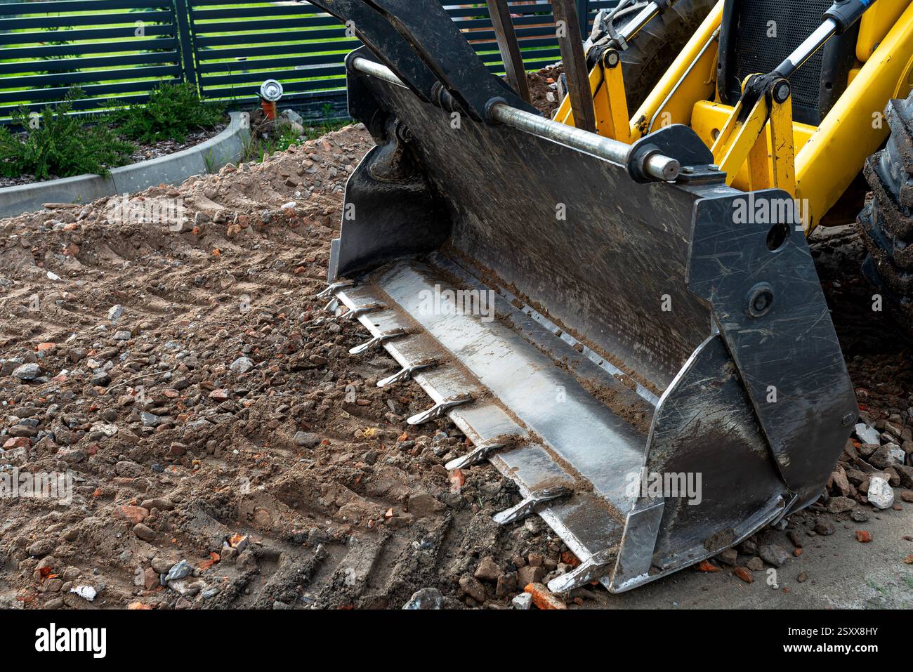A backhoe loader carries and levels rubble on a dirt road Stock Photo ...