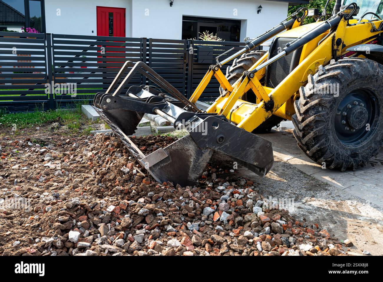 A backhoe loader carries and levels rubble on a dirt road Stock Photo ...