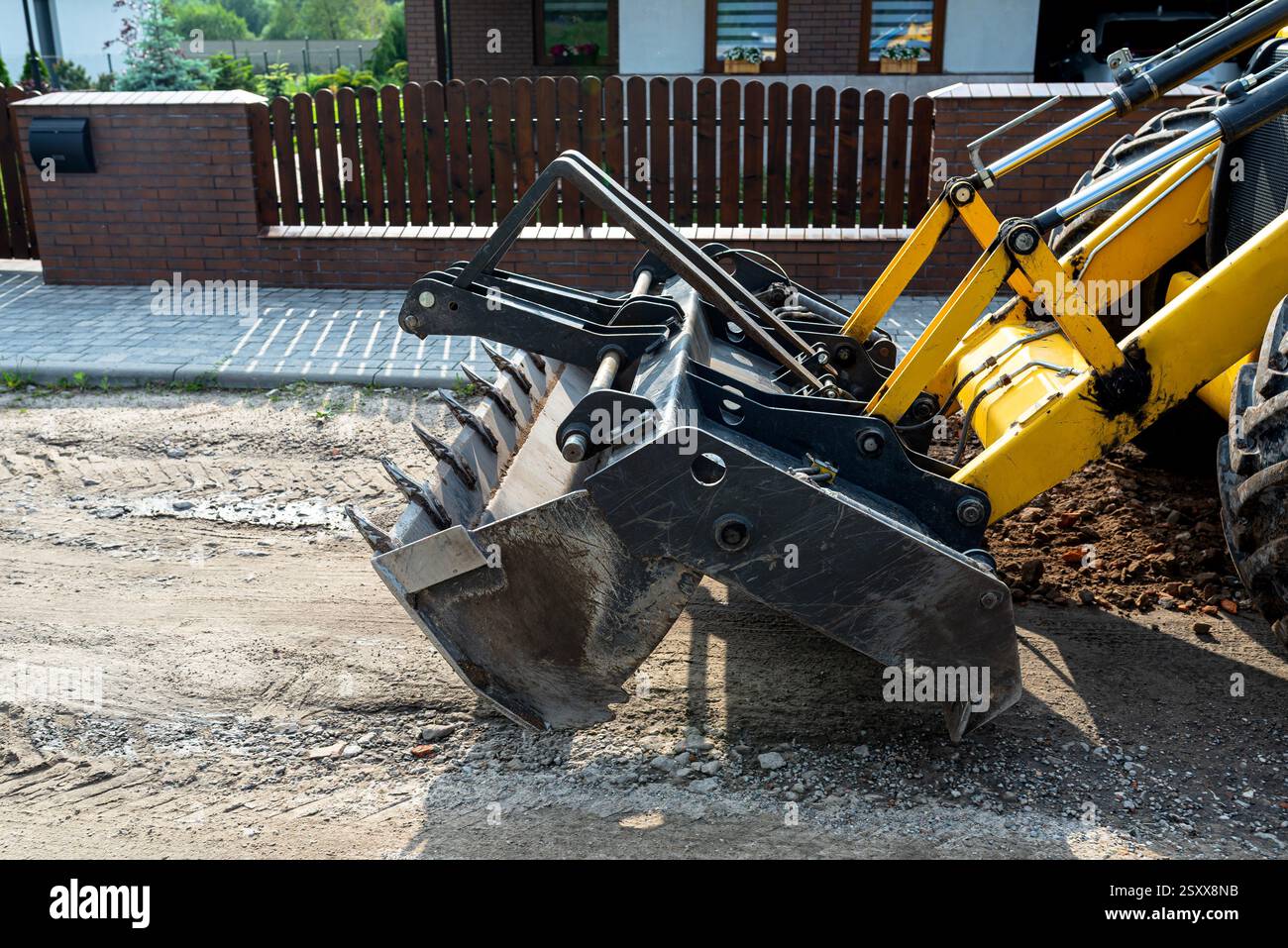 A backhoe loader carries and levels rubble on a dirt road Stock Photo ...