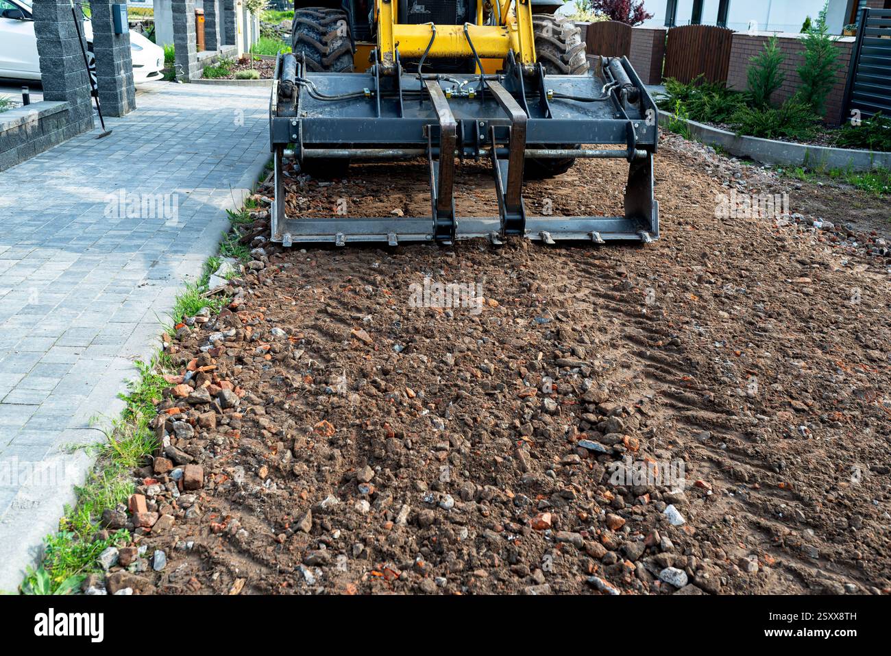 A backhoe loader carries and levels rubble on a dirt road Stock Photo ...