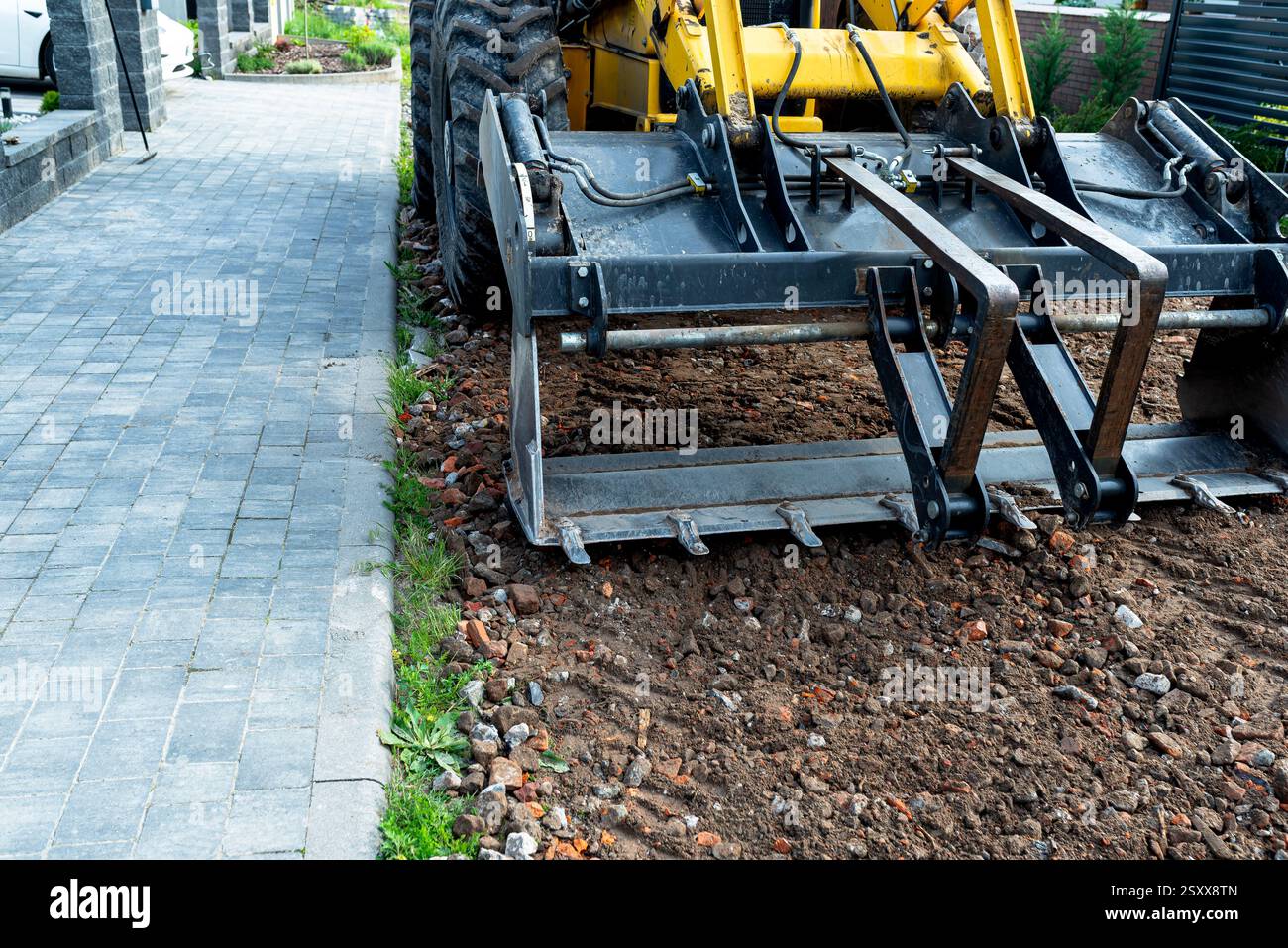 A backhoe loader carries and levels rubble on a dirt road Stock Photo ...