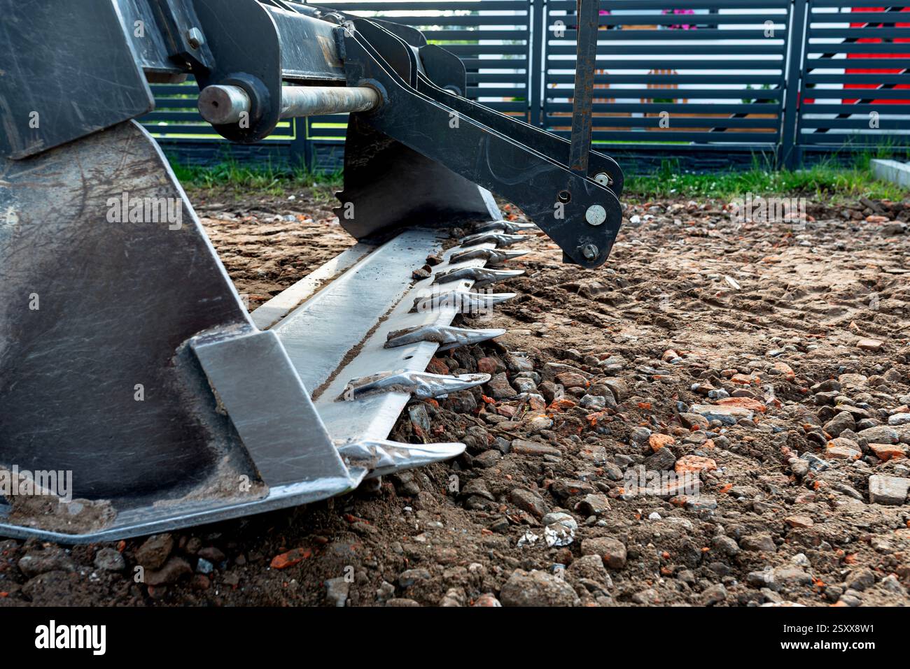A backhoe loader carries and levels rubble on a dirt road Stock Photo ...