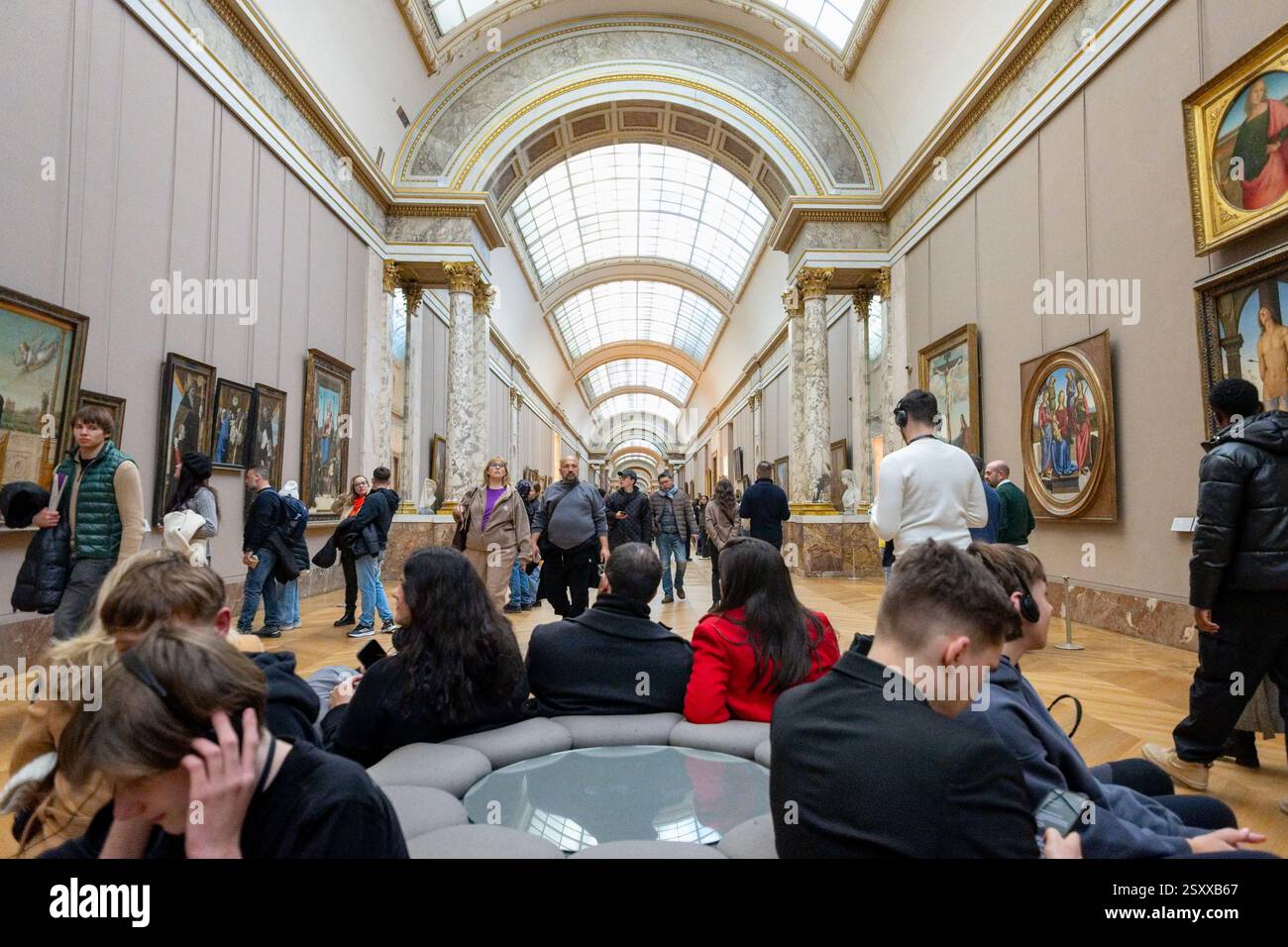 Visitors exploring the magnificent Grande Galerie of the Louvre Museum ...