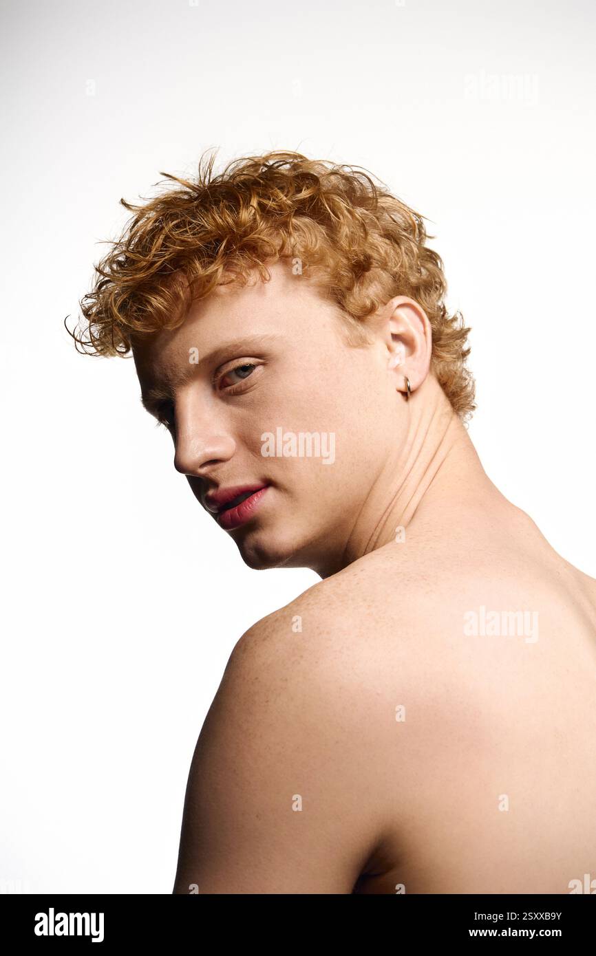 A young handsome man with curly ginger hair showcases a trendy look ...