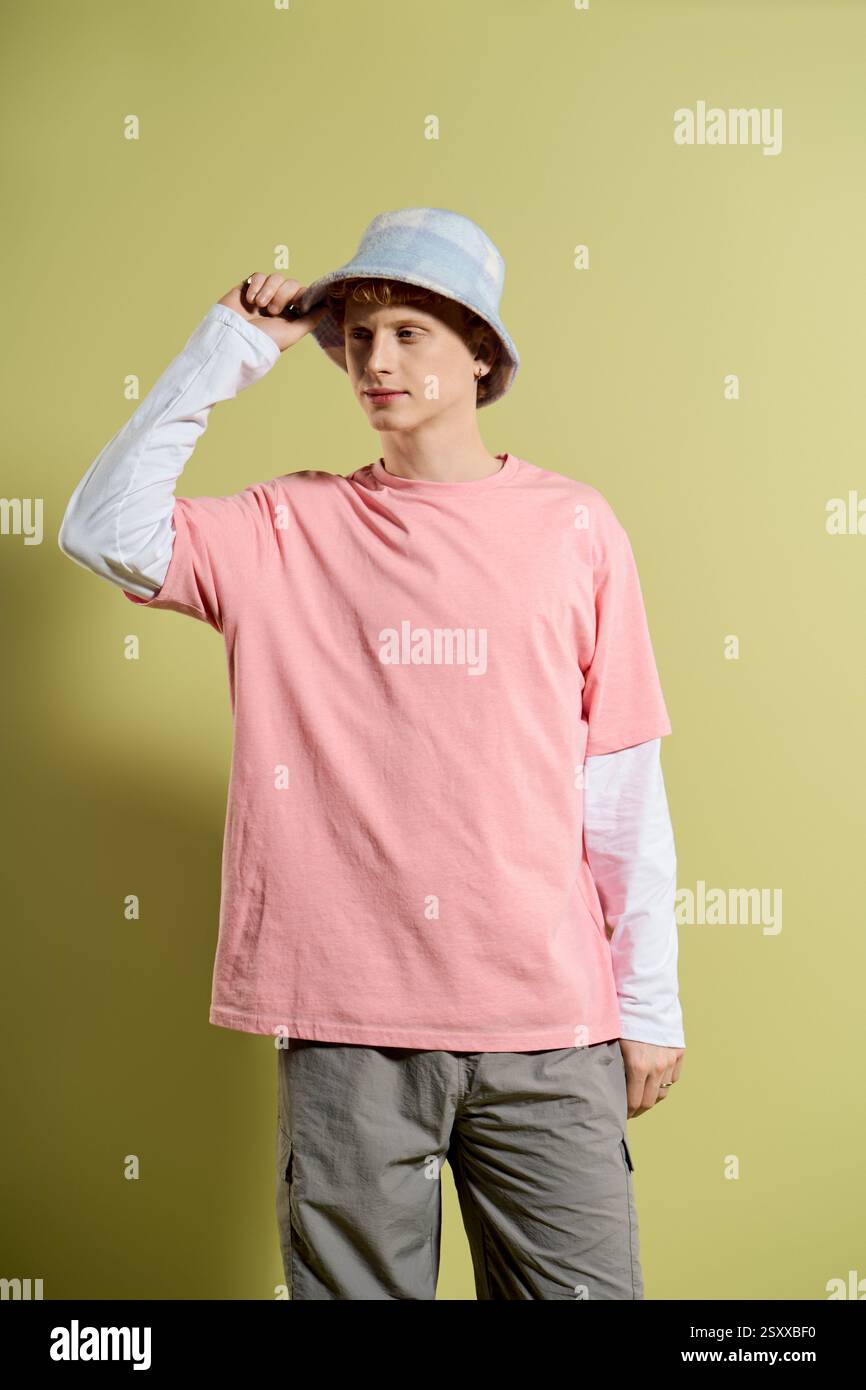 A stylish young man poses confidently in a pink shirt and bucket hat ...