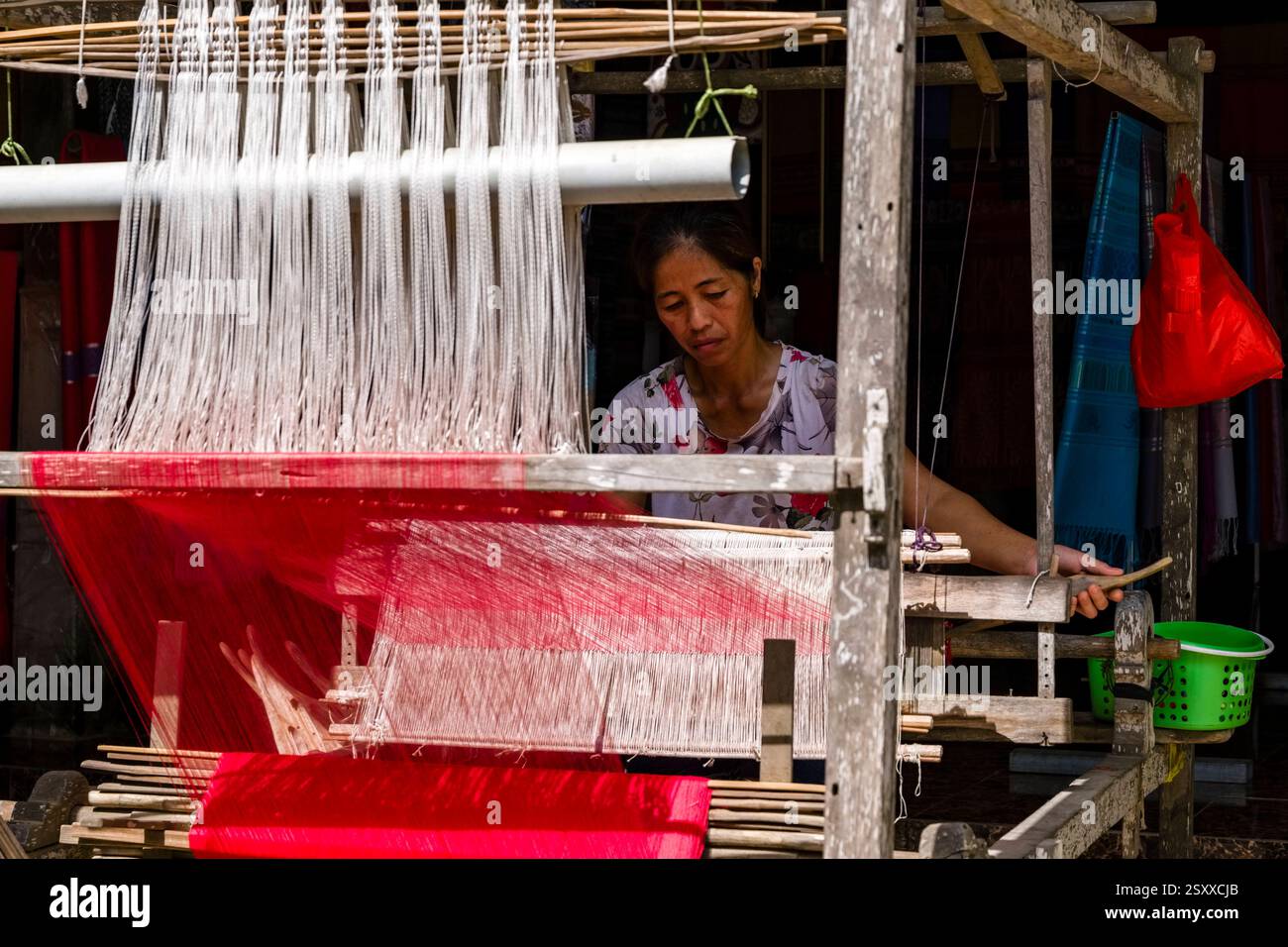 A local woman weaves fabric on a traditional wooden loom in Mai Chau ...