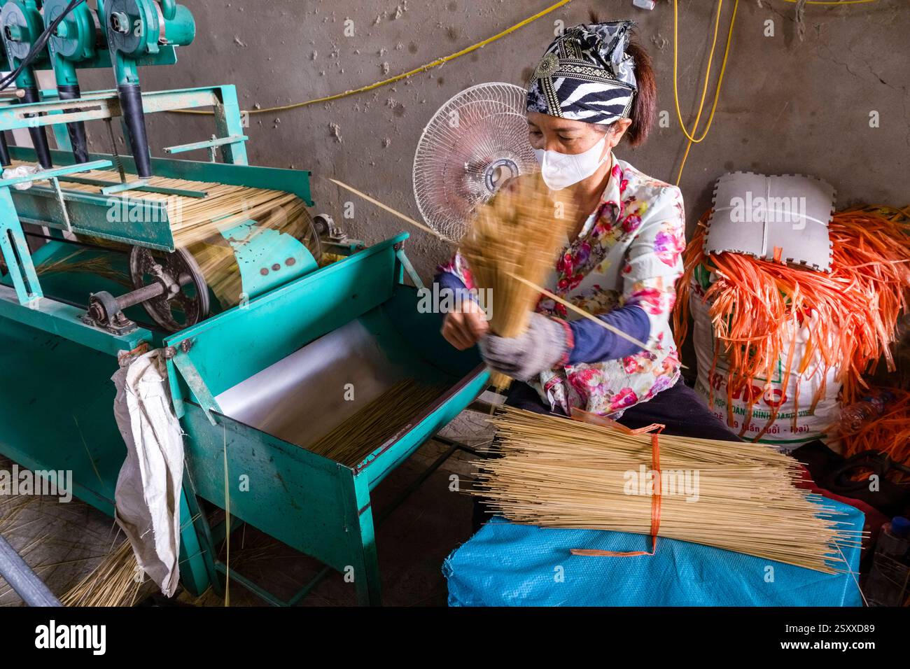 A woman bundles split thin bamboo sticks for the later production of ...