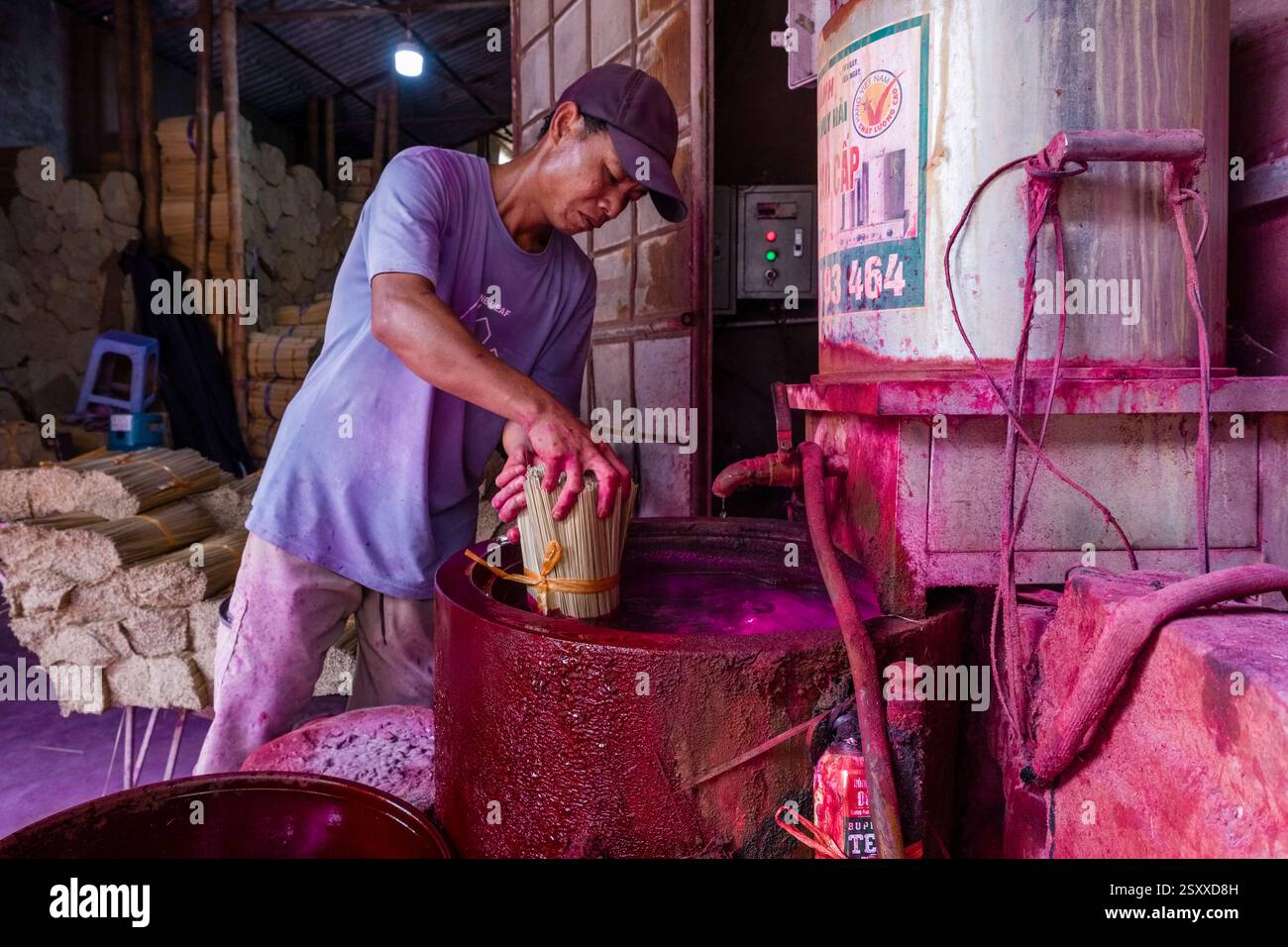 A man dyes split thin bamboo sticks with red paint for the later ...