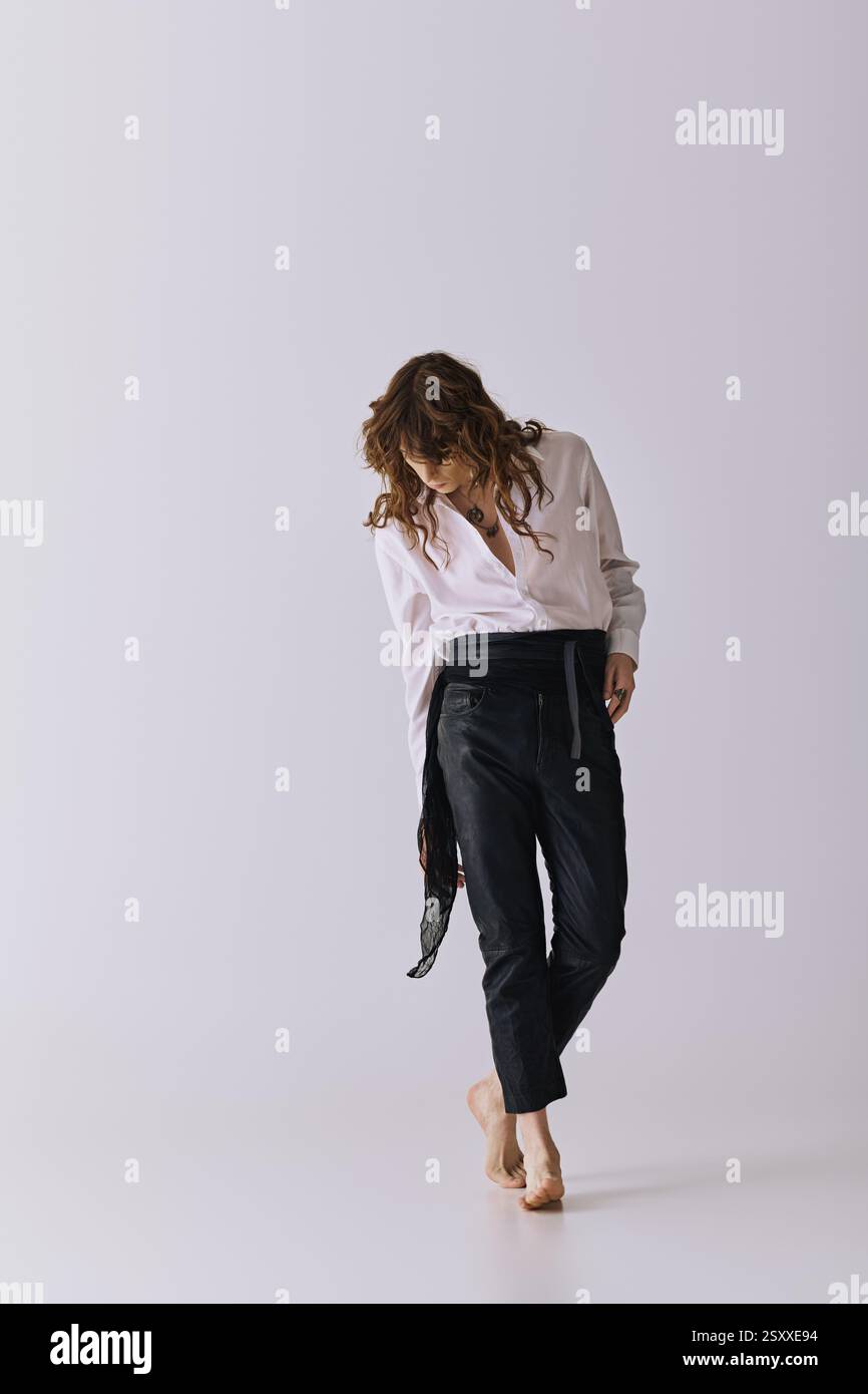 A stylish young man poses barefoot indoors, exuding charm and elegance ...