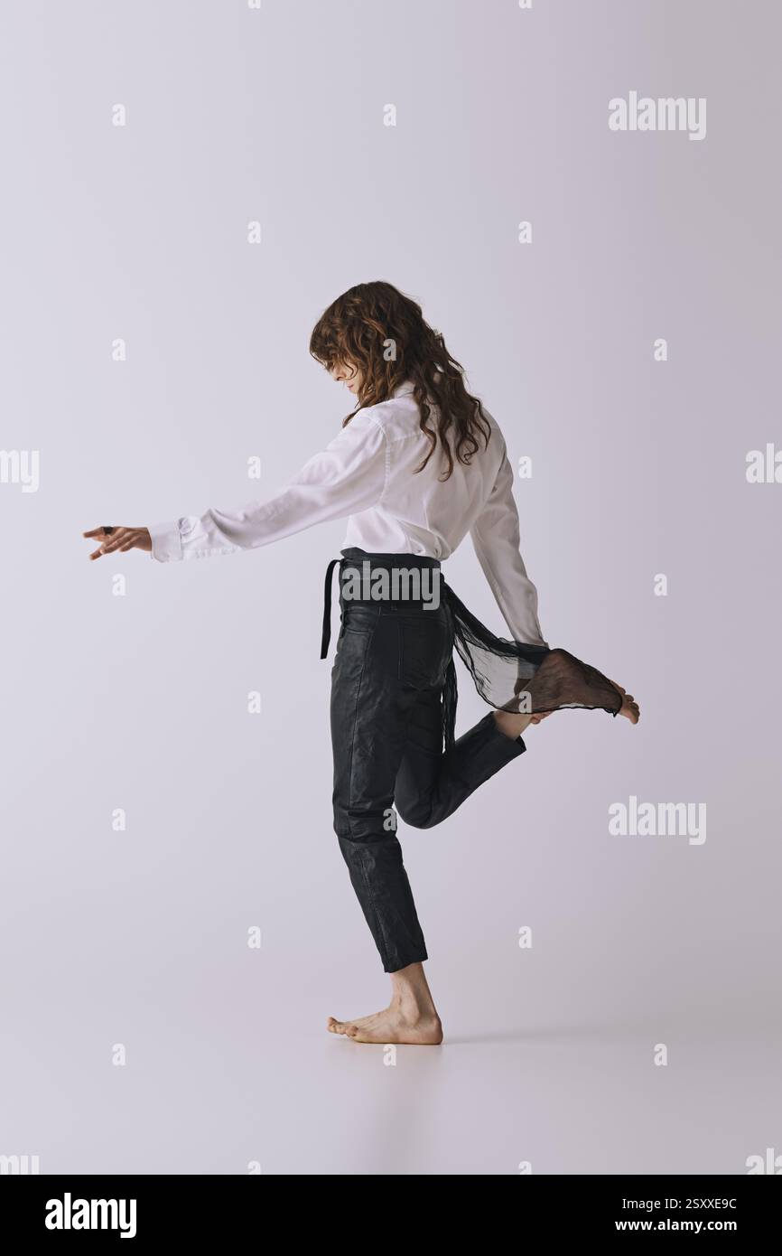 A handsome young man showcases his elegance while dancing barefoot in a modern studio Stock ...