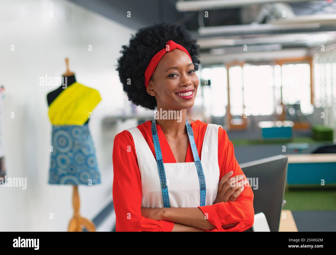 Fashion designer smiling confidently in studio with mannequin and ...