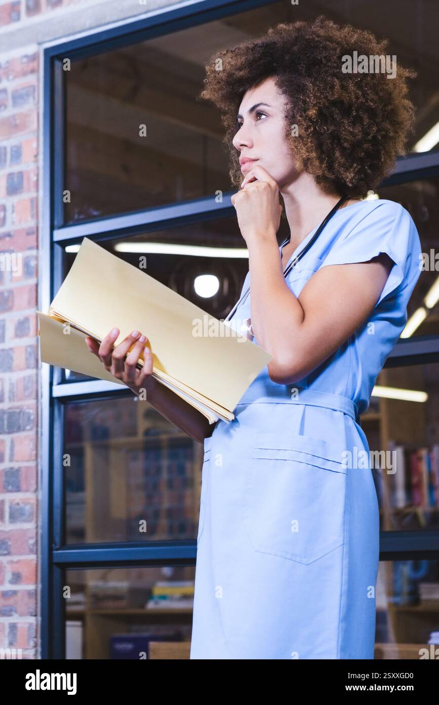 Professional woman in blue uniform holding files, thinking in modern ...