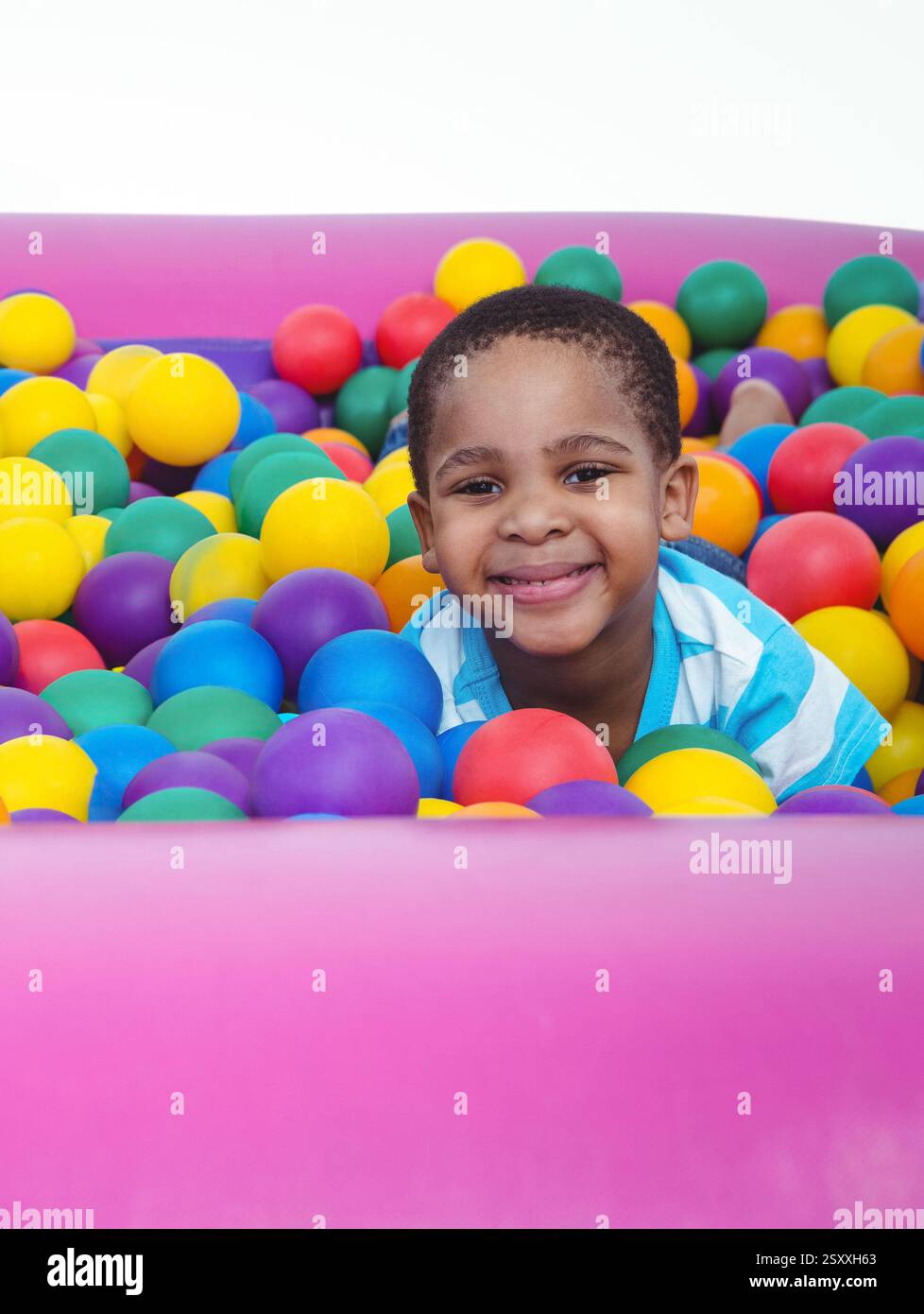 Smiling African American boy playing in colorful ball pit, enjoying fun ...