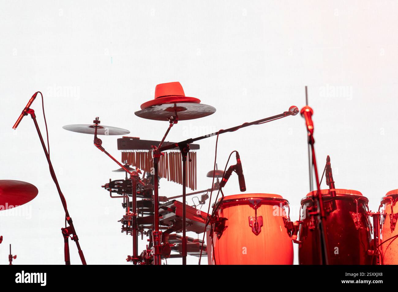 A stage drum set is illuminated by red lighting, featuring various ...