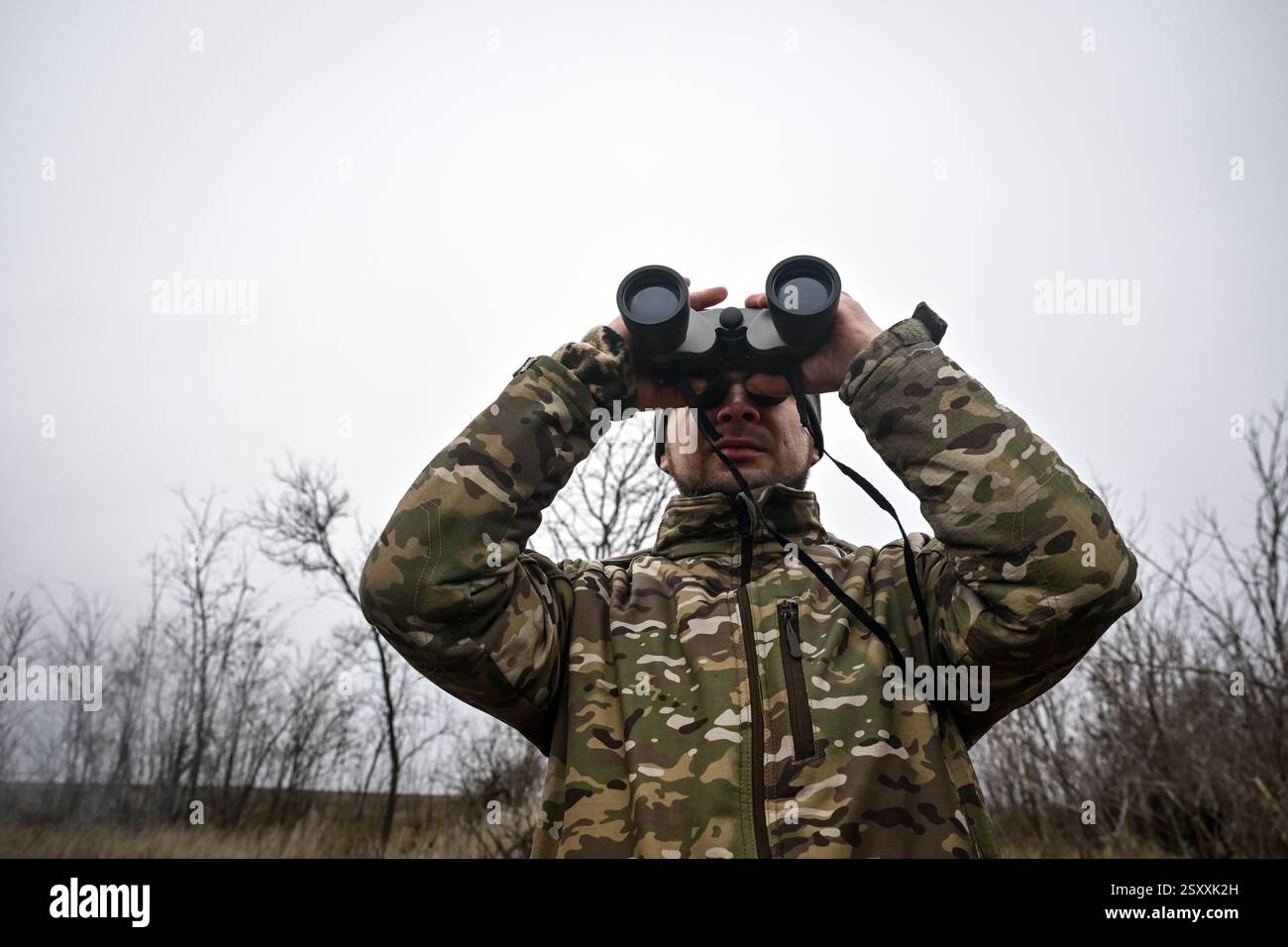 A soldier uses binoculars during a live fire exercise of a tank ...