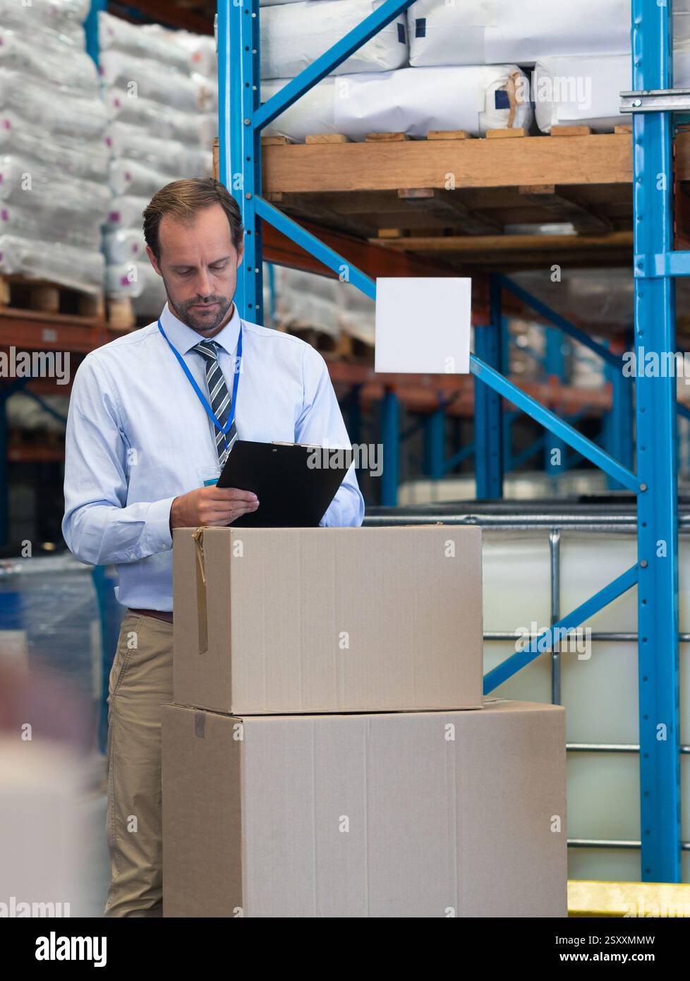 Warehouse manager checking inventory with clipboard, focusing on ...
