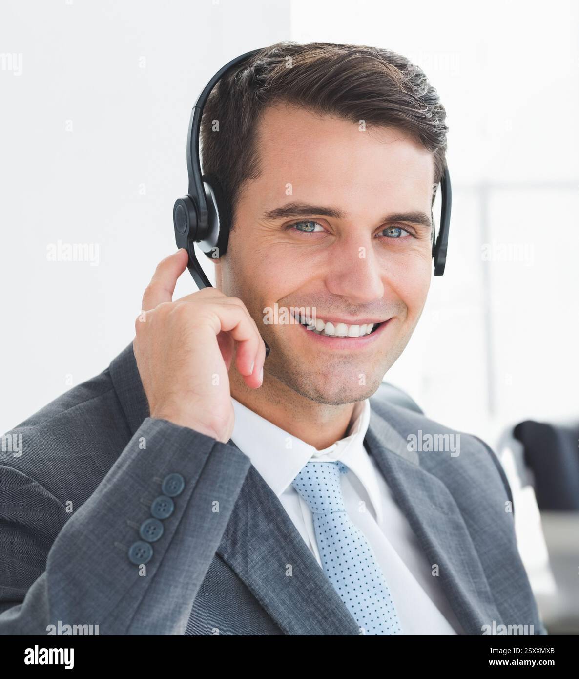Smiling businessman using headset for communication in modern office ...