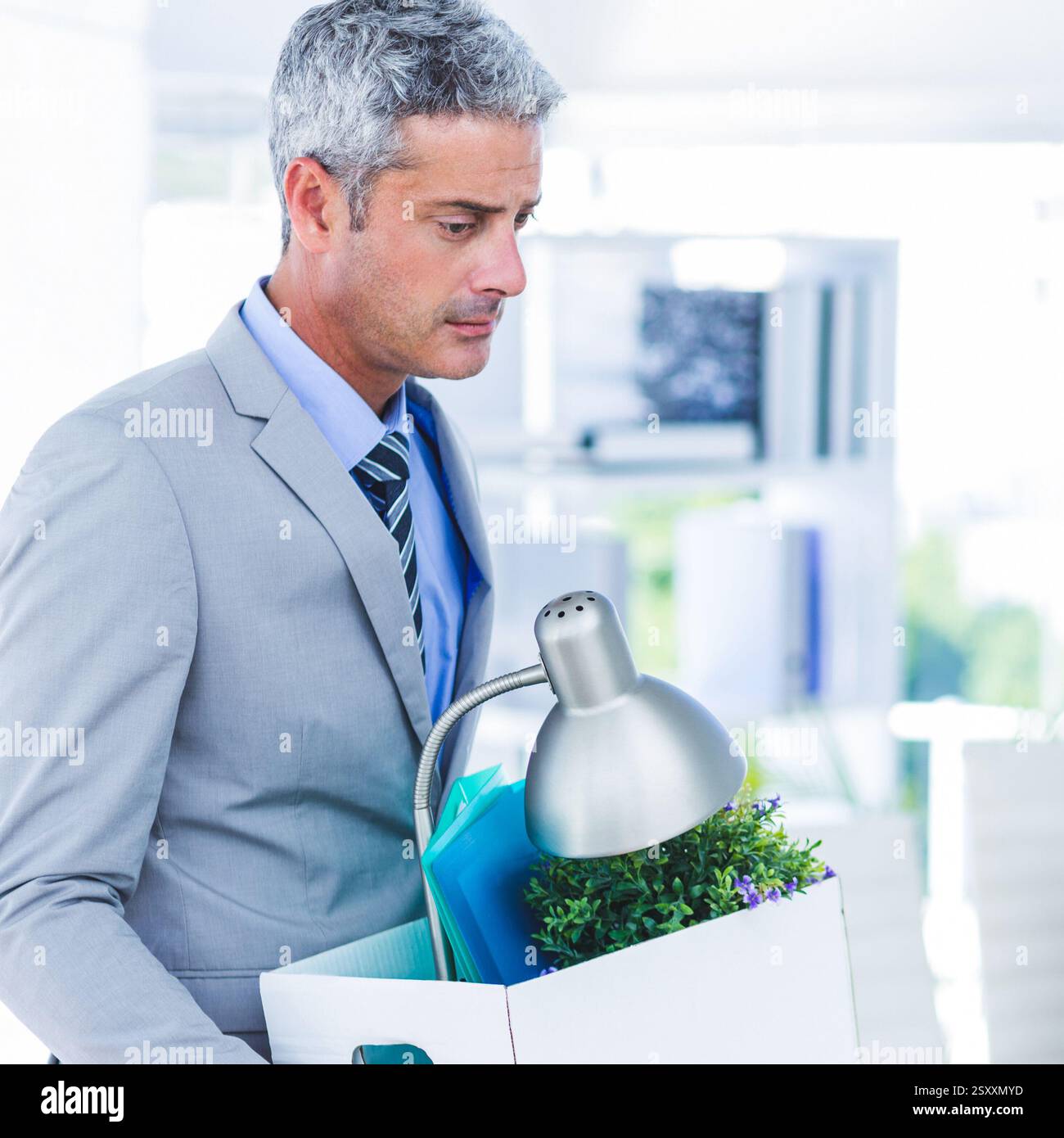 Carrying office items in box, businessman leaving workplace with ...