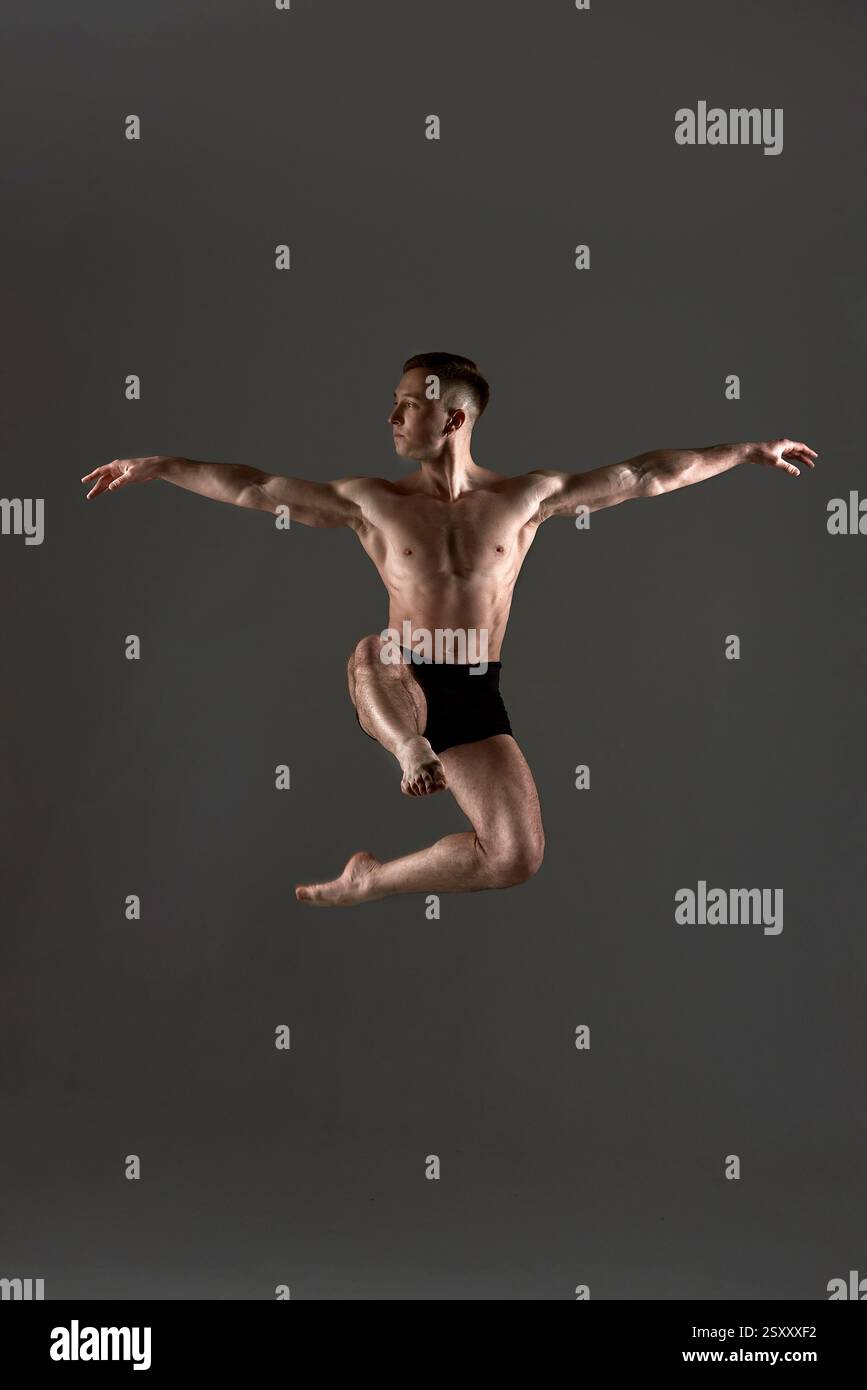 Muscular male dancer performing a dynamic mid-air jump. Toned physique and expressive pose ...