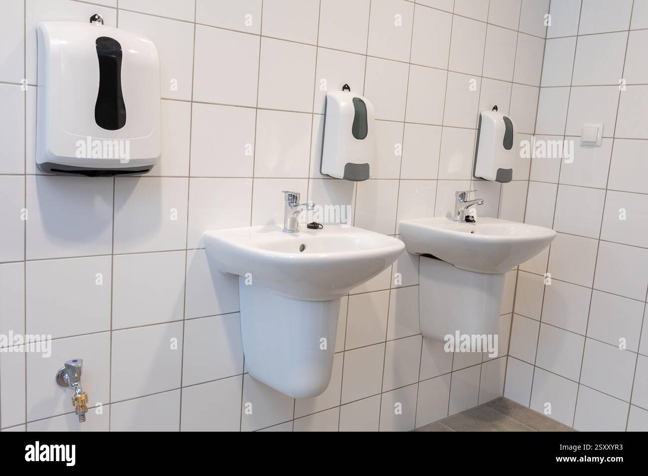 A modern public restroom with multiple sinks and hand dryers for ...