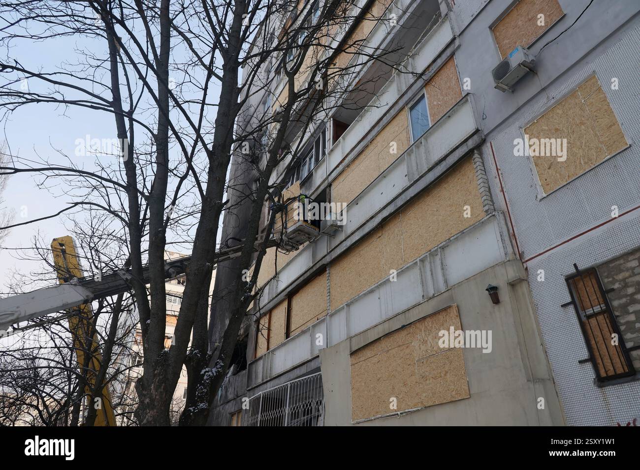 Municipal workers use an aerial work platform to seal windows in an ...