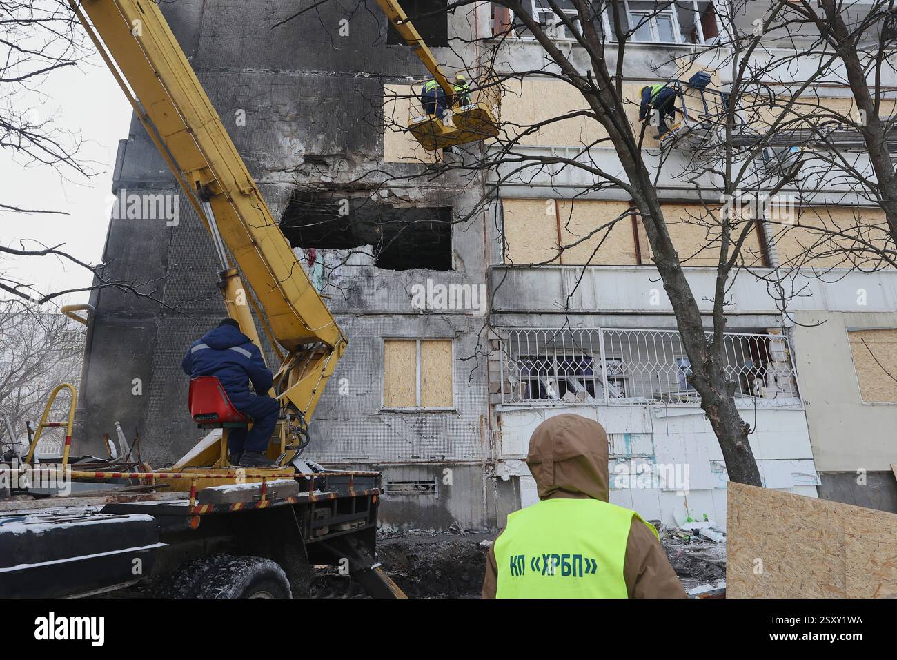 Municipal workers use an aerial work platform to seal windows in an ...