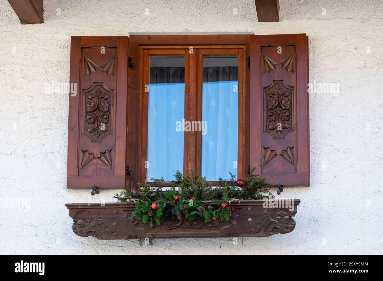 Traditional Alpine window with decorative wooden shutters and winter ...