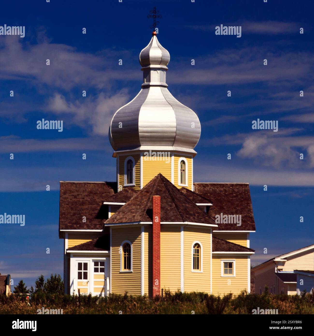 Yellow church with a steeple. The roof is made of wood. The building is ...