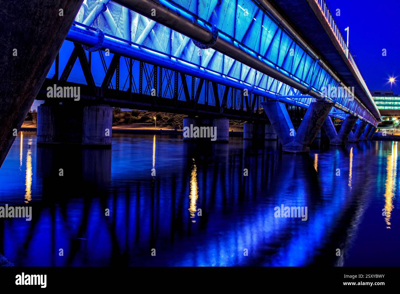 Bridge with lights on it. The lights are blue. The water is reflecting ...