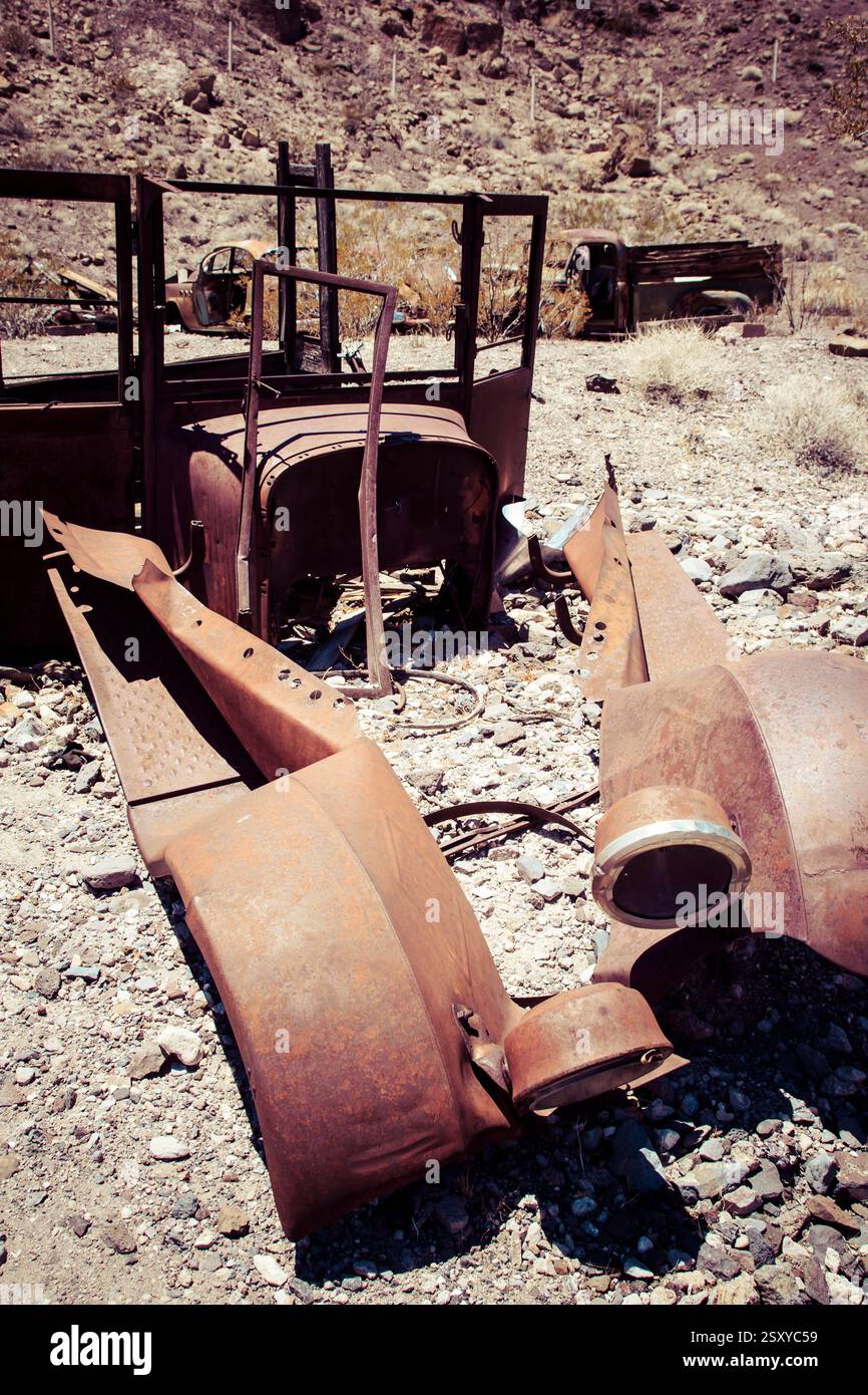 Rusted old car is sitting on the side of the road. The car is missing ...