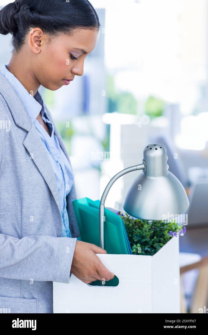 Businesswoman carrying office items in box, leaving workplace with ...