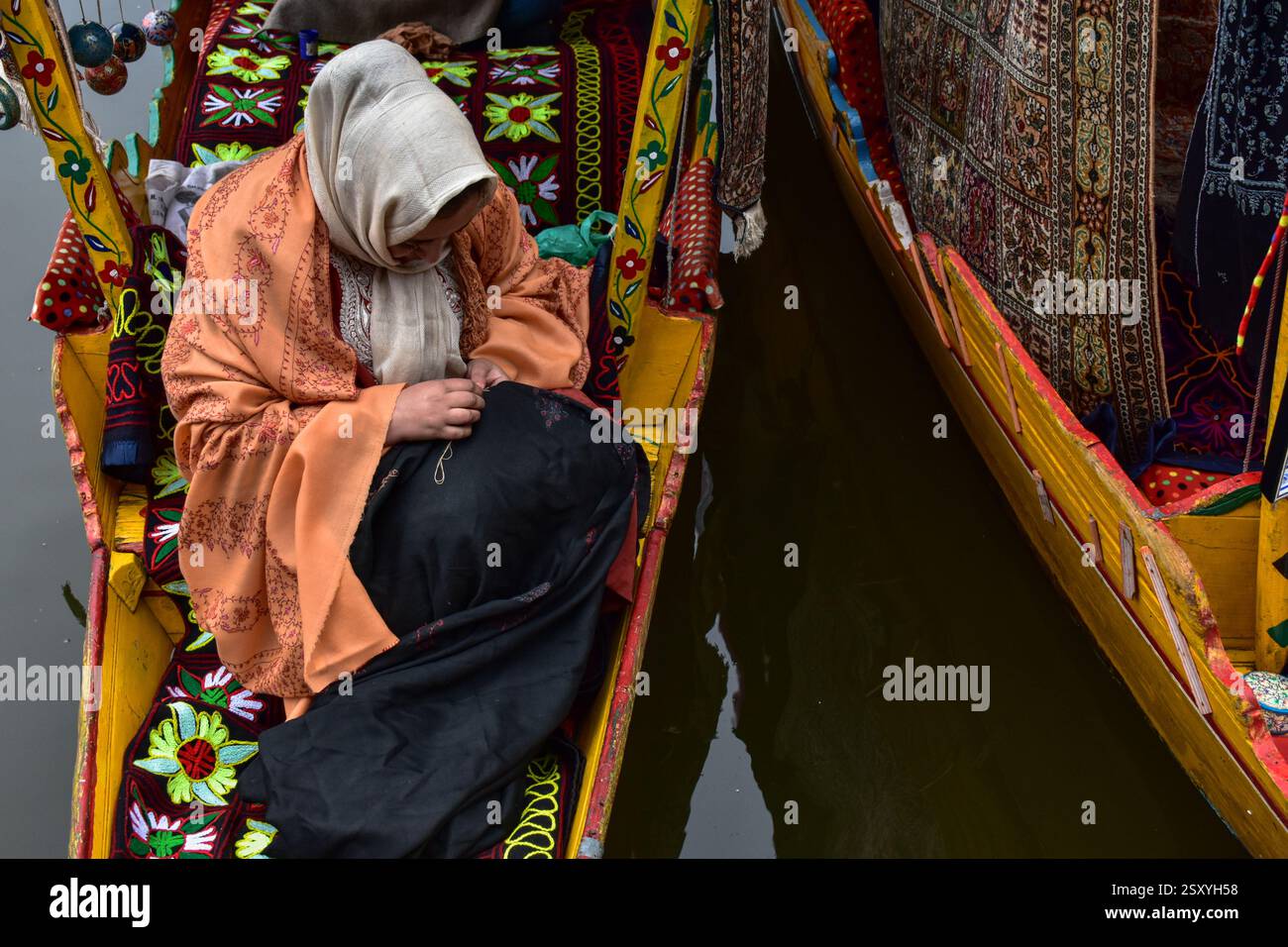 A Kashmiri artisan sewing intricate designs onto a Kashmiri shawl ...