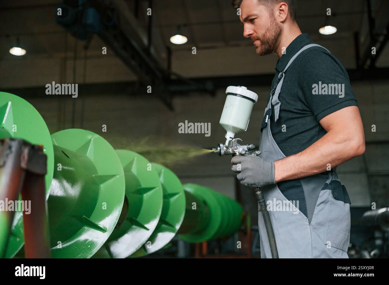 Painting details to green color. Man in uniform is in workstation ...
