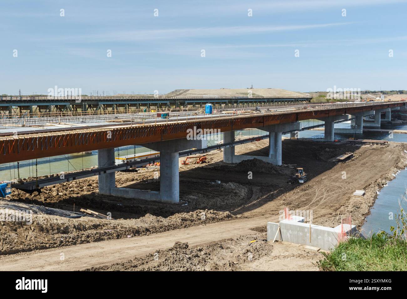Bridge is being built over a river. There are two workers on the bridge ...