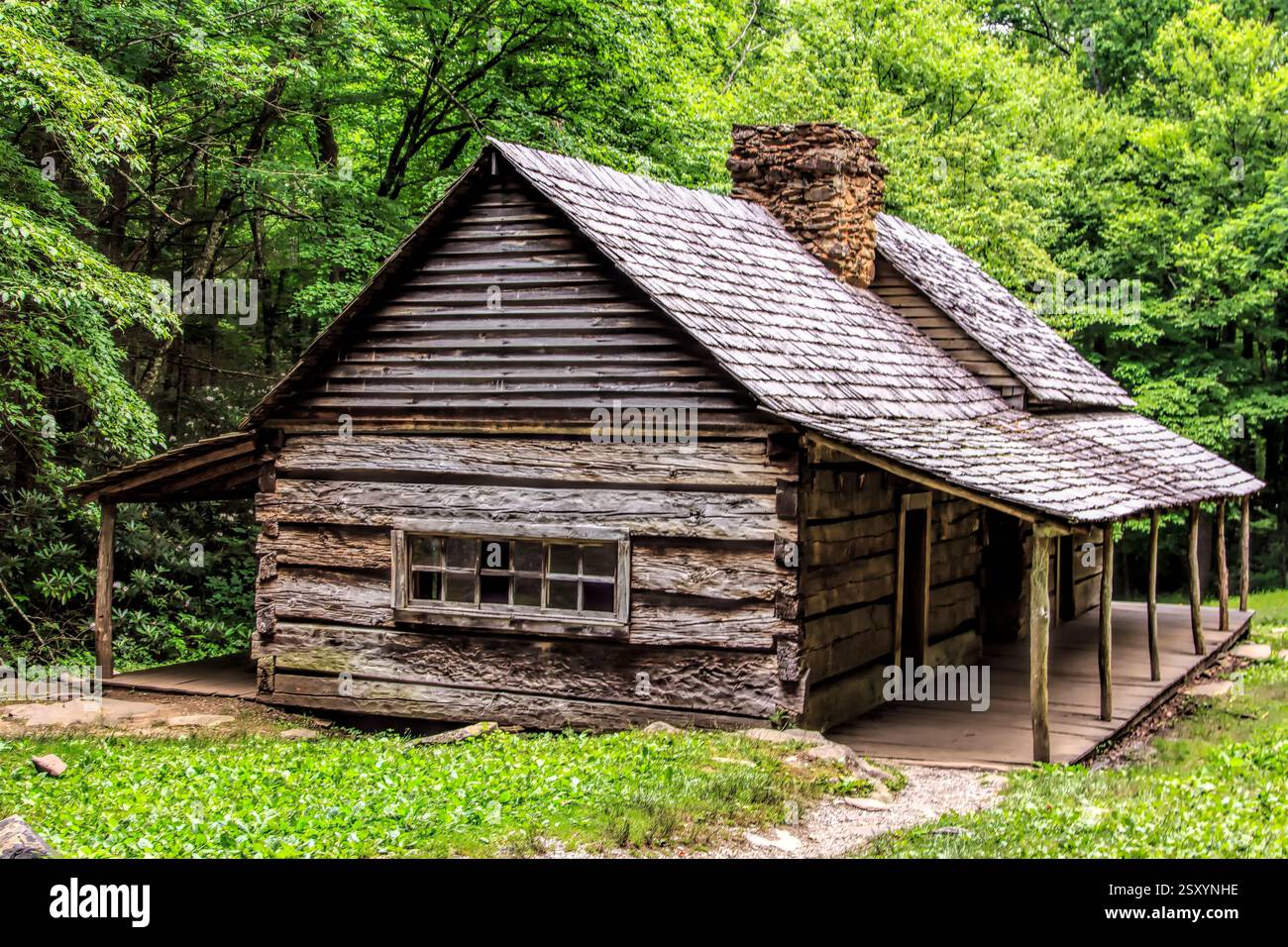 Log cabin with a porch and a chimney. The roof is made of wood shingles ...