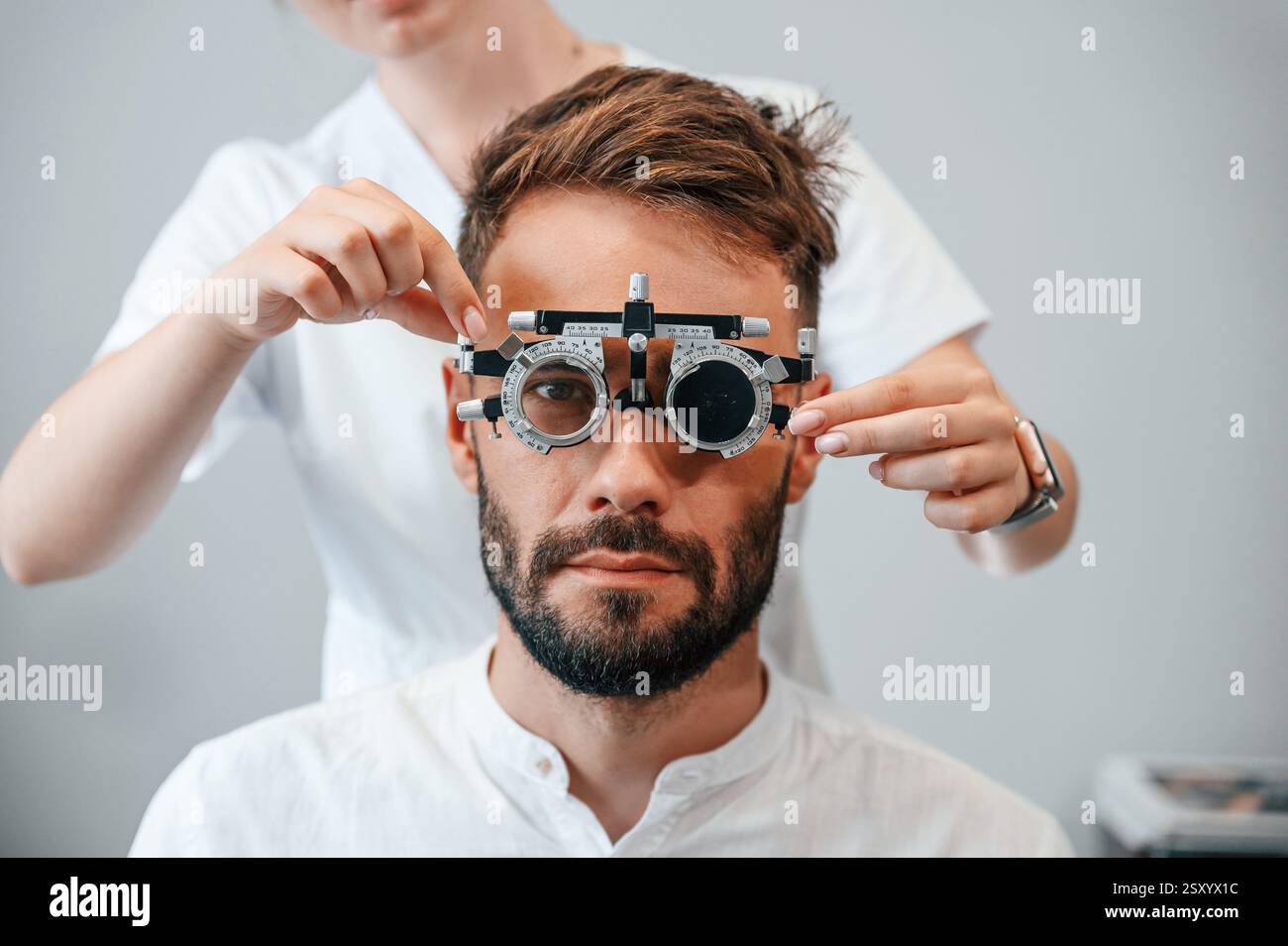 Optometric device. Man's vision checked by female doctor in the clinic ...