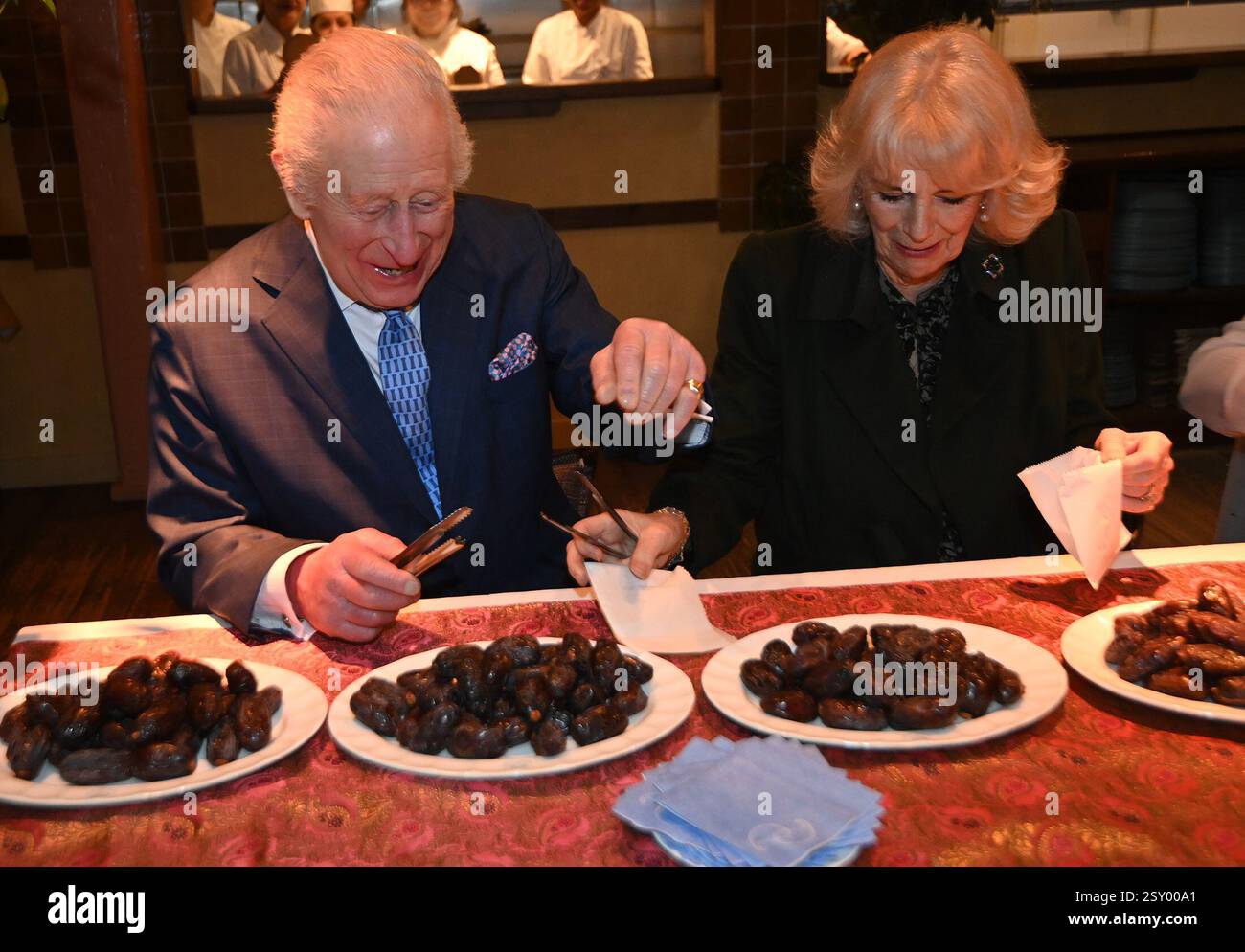 King Charles III and Queen Camilla help pack donation bags as they meet ...