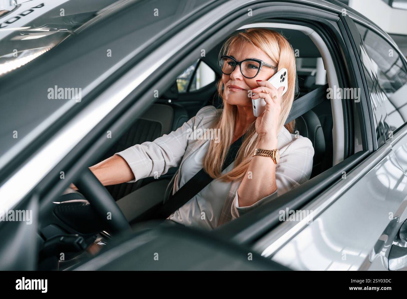 Driving new automobile. Woman in white formal clothes is in the car ...