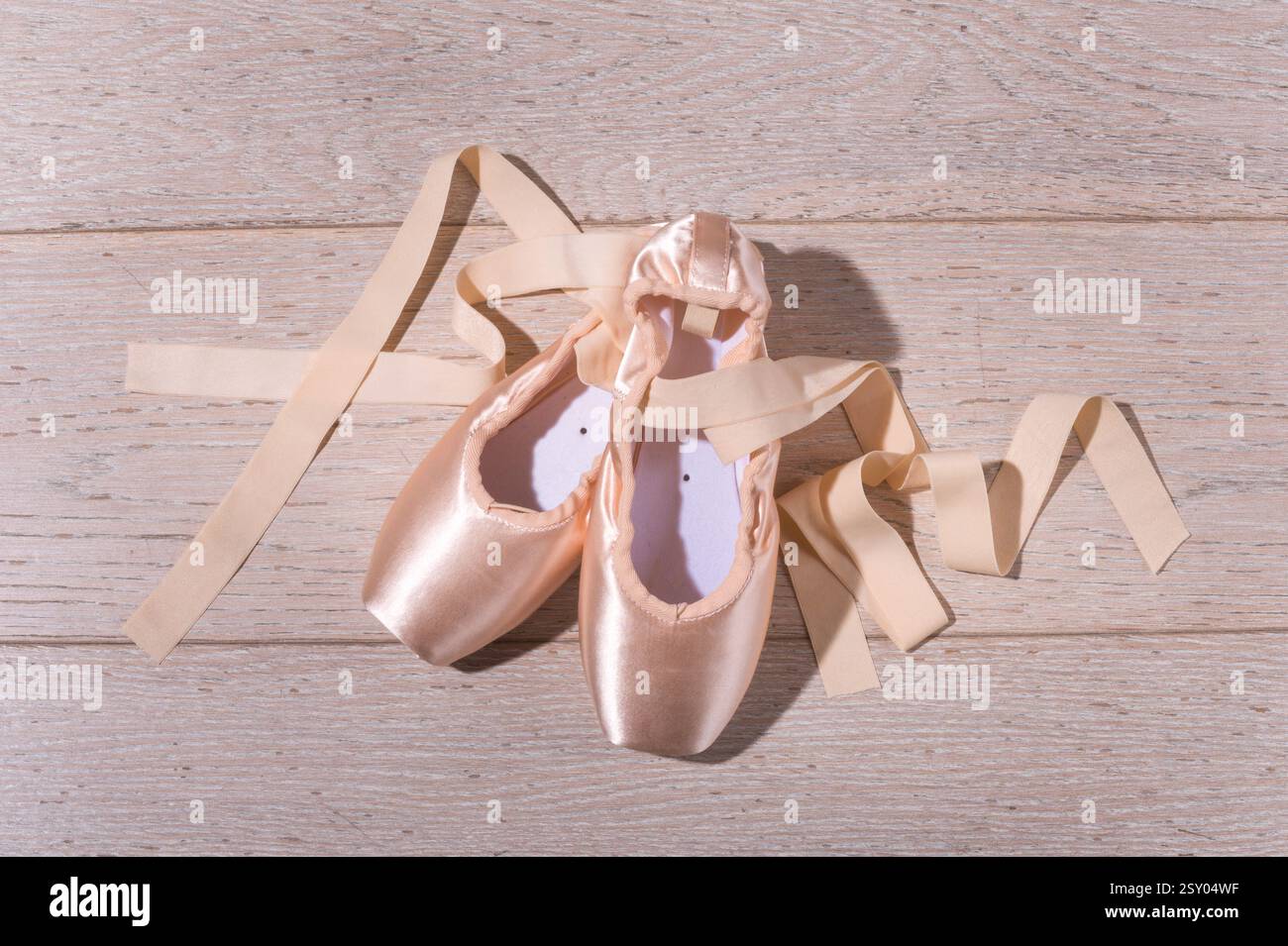 Satin pointe shoes on wooden floor, suggesting a concept of classical dance and artistic hobbies ...